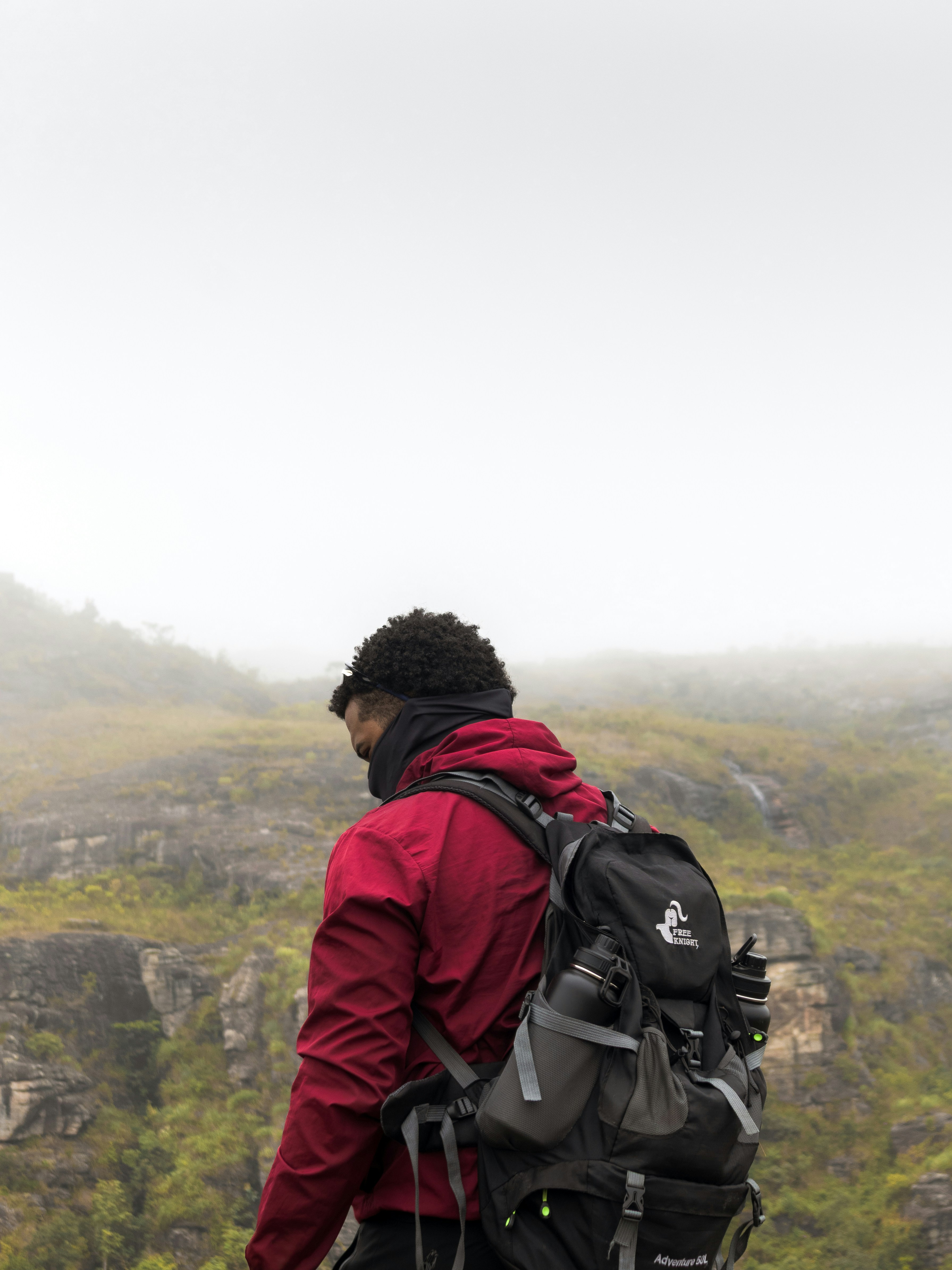 Hiker at the Edge: Red Jacket Against Shrouded Cliffscape