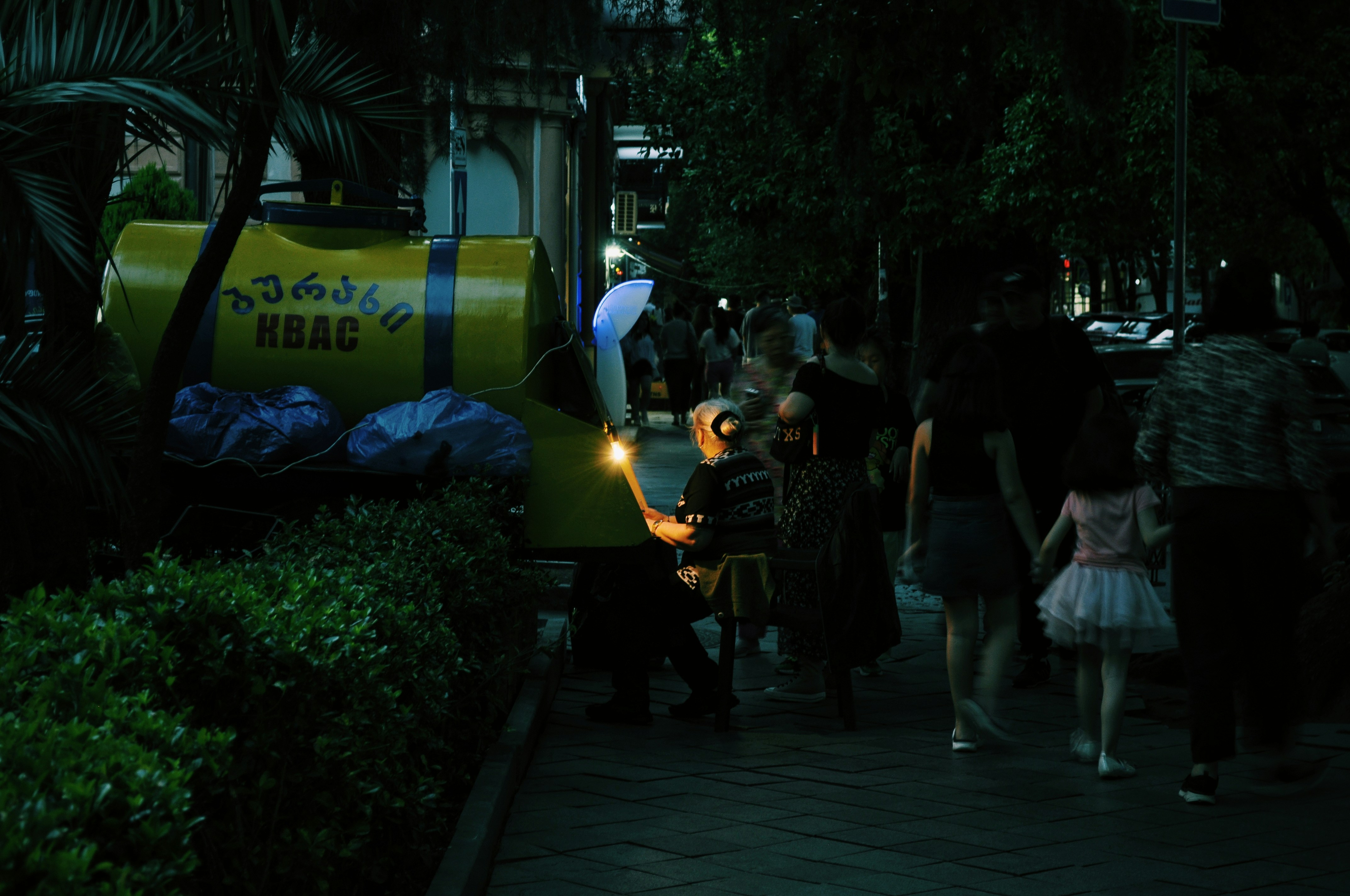 Dark street, a lone flame: a street performer with a glowing torch amid a quiet crowd