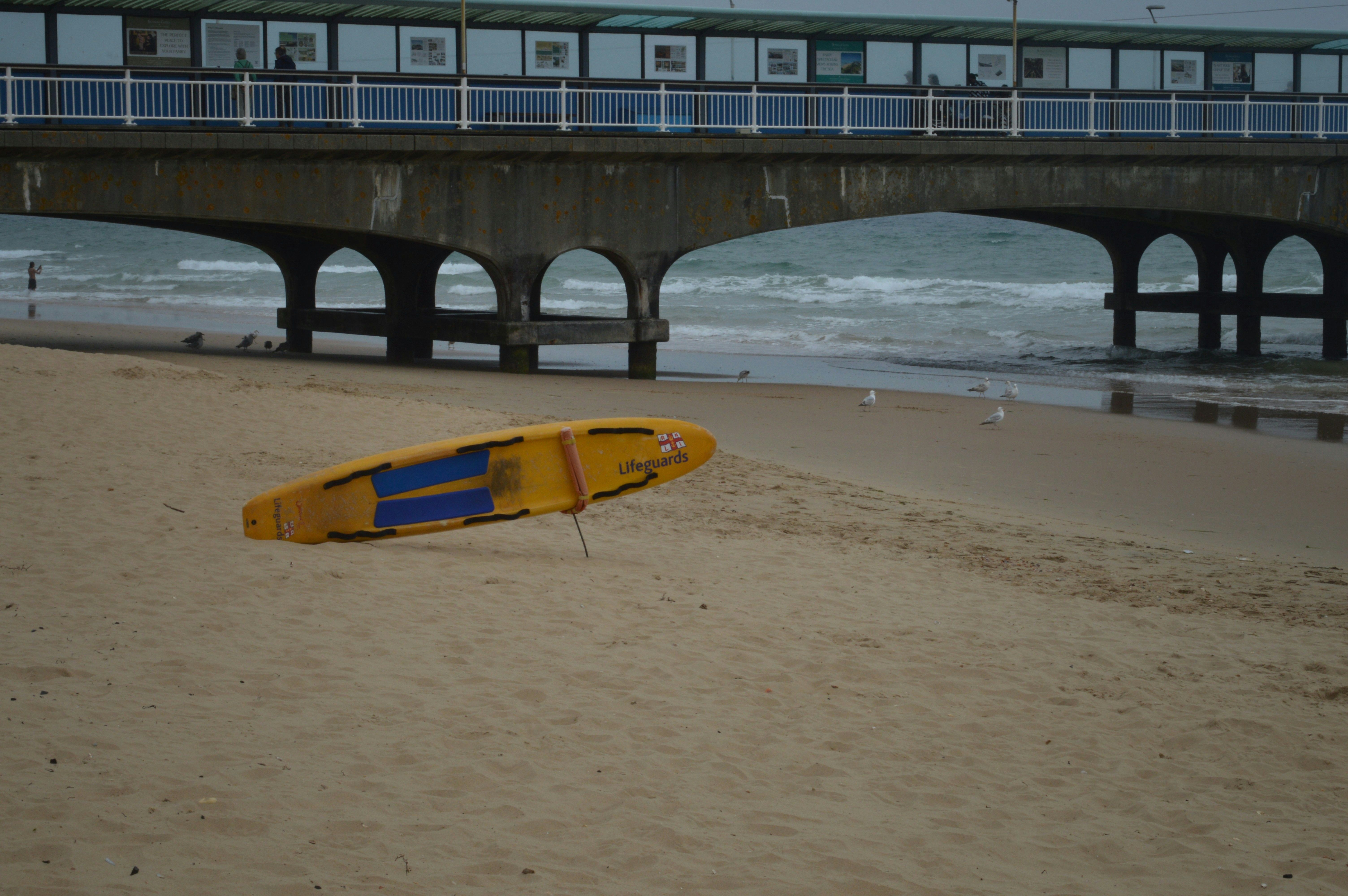 Orange Lifeguard Boat on Quiet Beach Beneath Pier