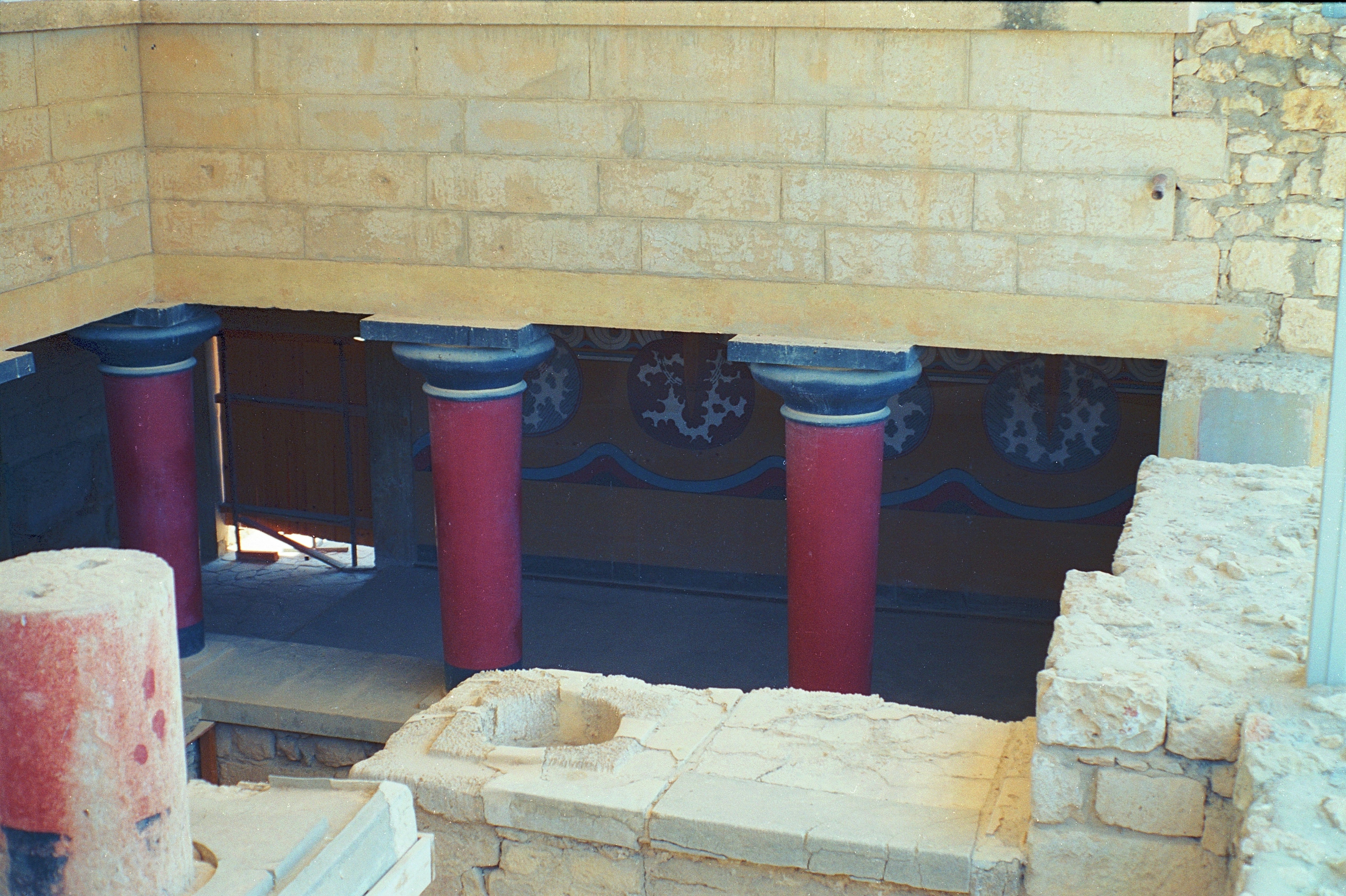 Ancient Hallway Revealed: Crumbling Walls and Red Columns Framing a Hidden Corridor