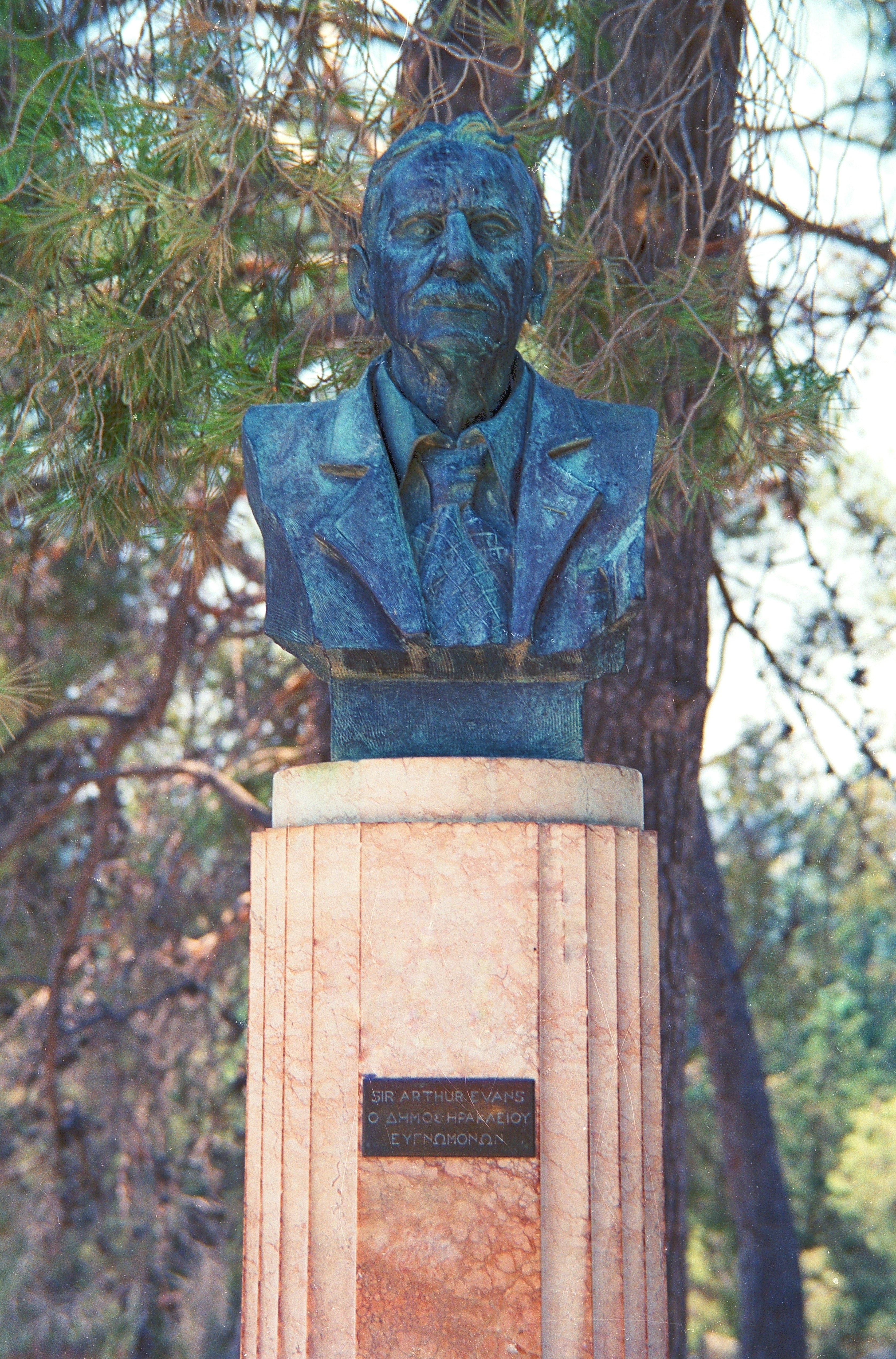 Blue-tinted bust under pine branches on a stone pedestal
