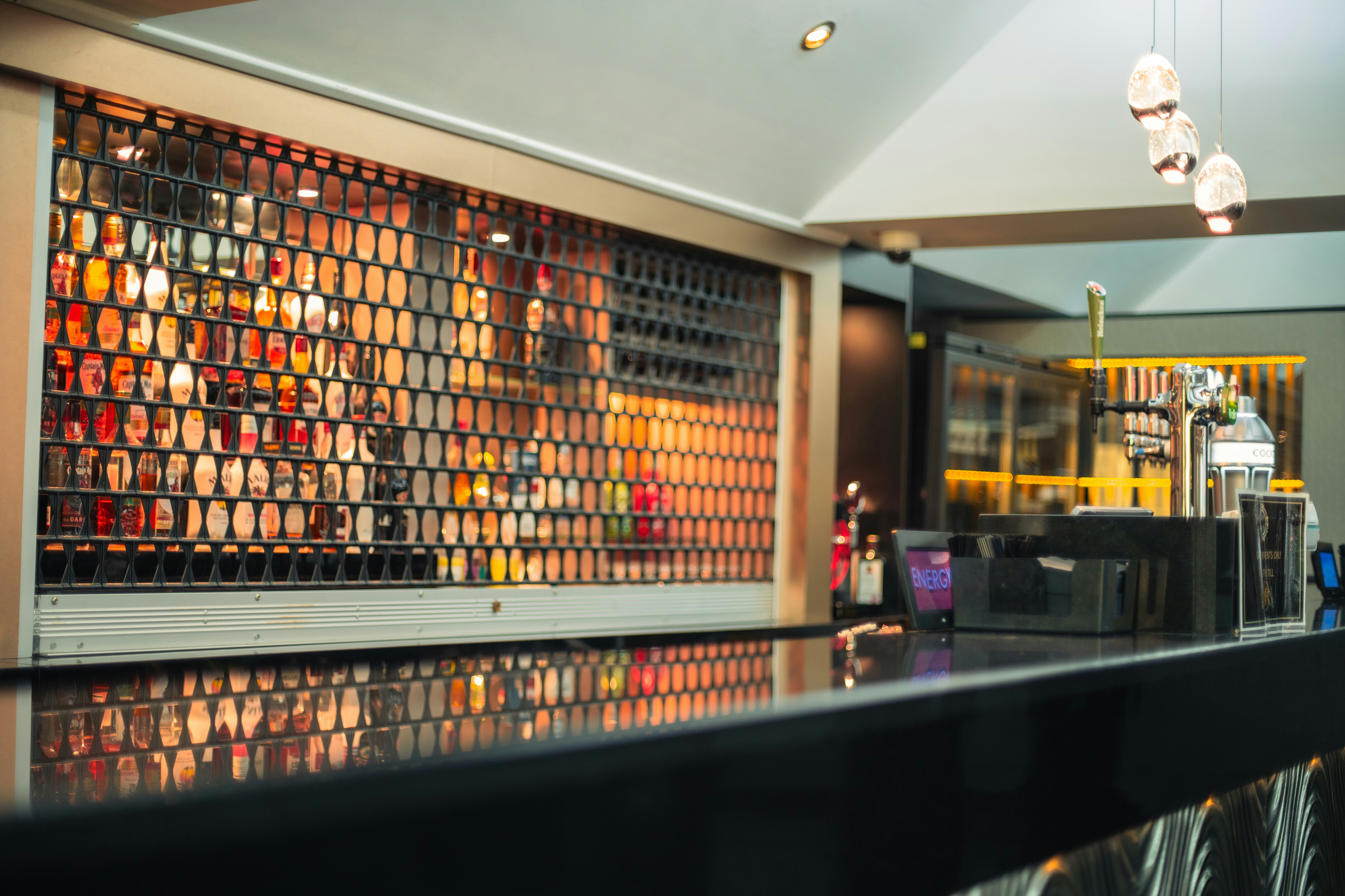 Reflections and Neon Rows: A Quiet Bar Shelf Across the Frame