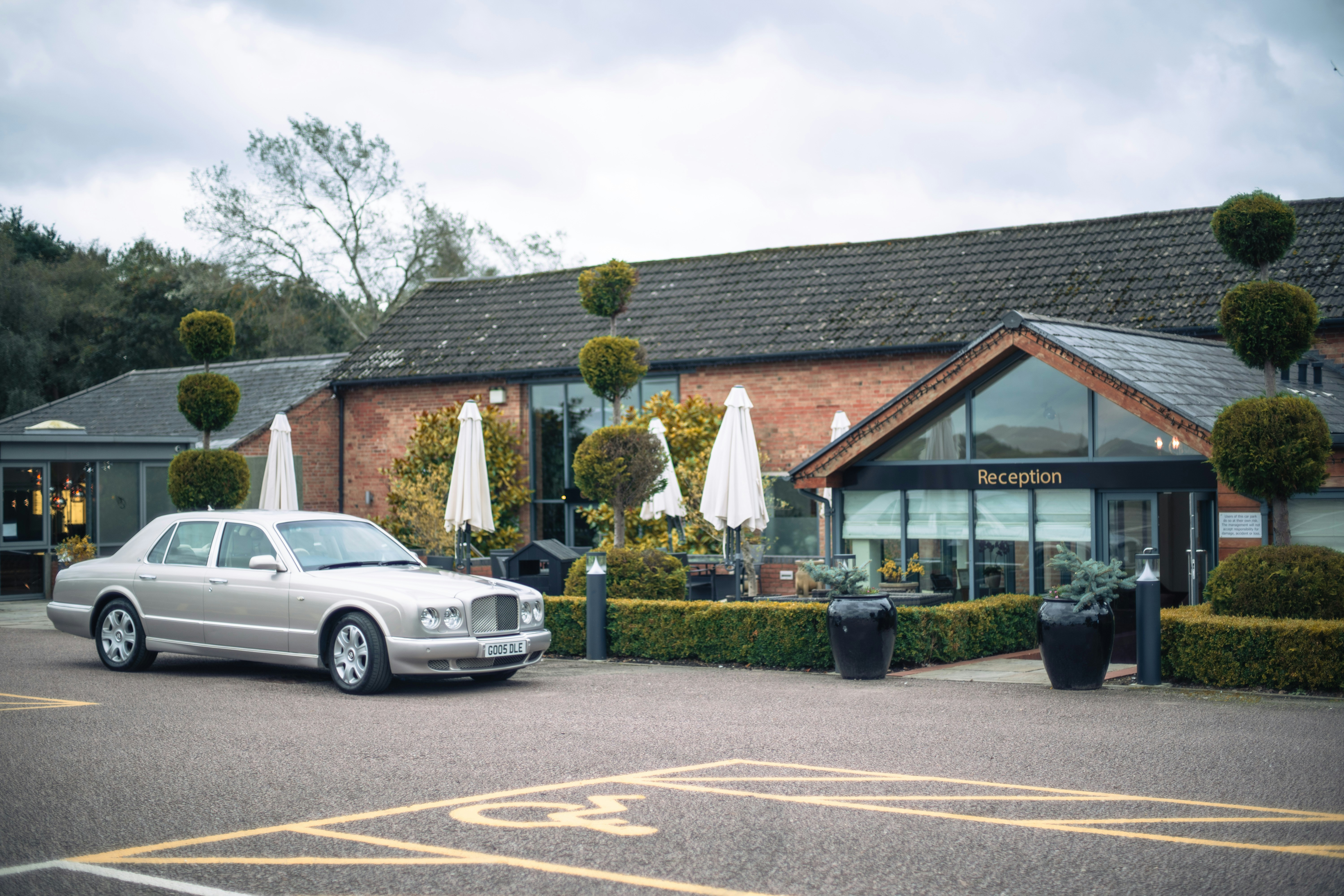 Luxe Arrival: Classic Silver Car at a Quiet Hotel Entrance