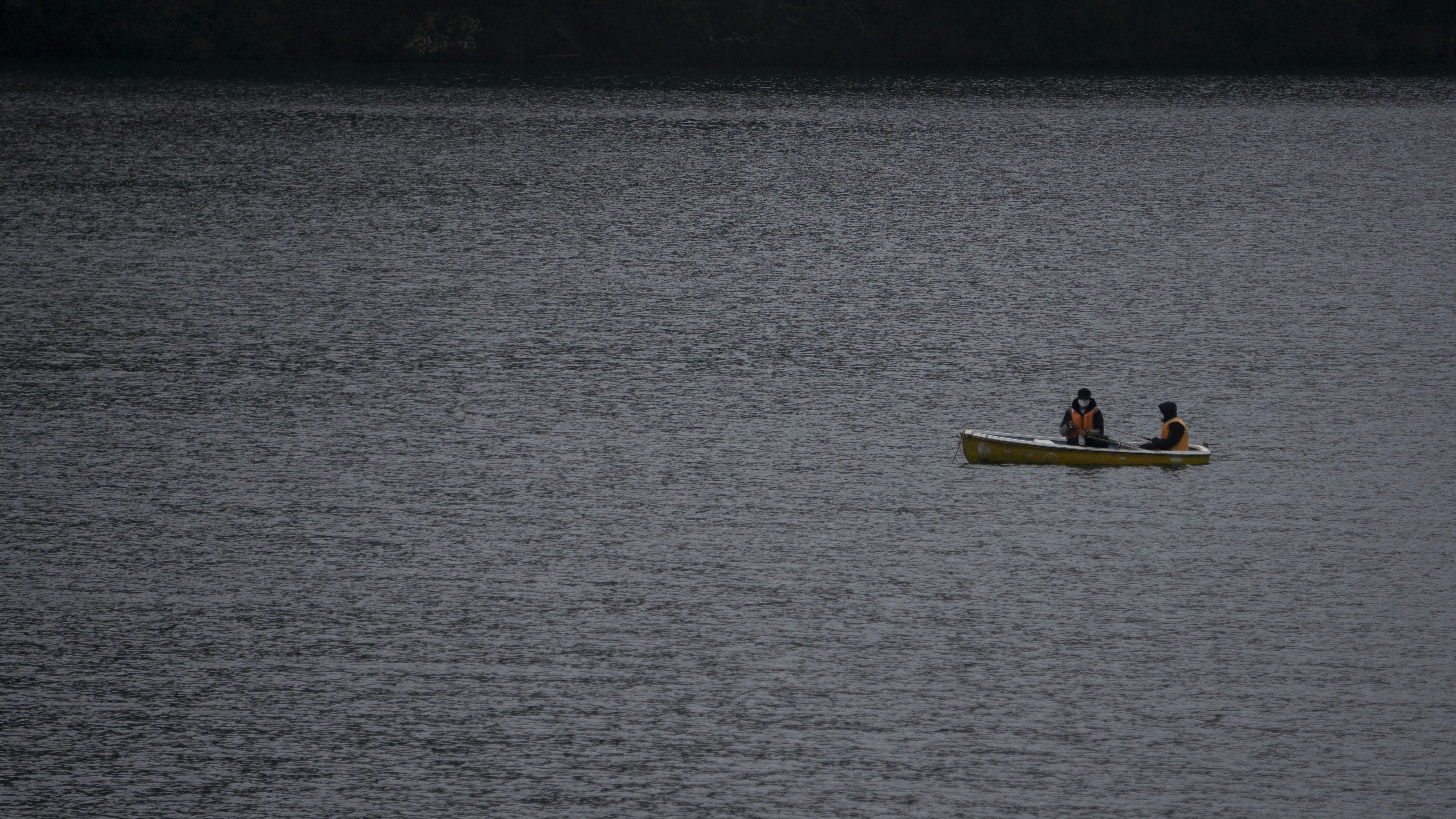 Two Figures adrift: a lone rowboat cutting a quiet horizon