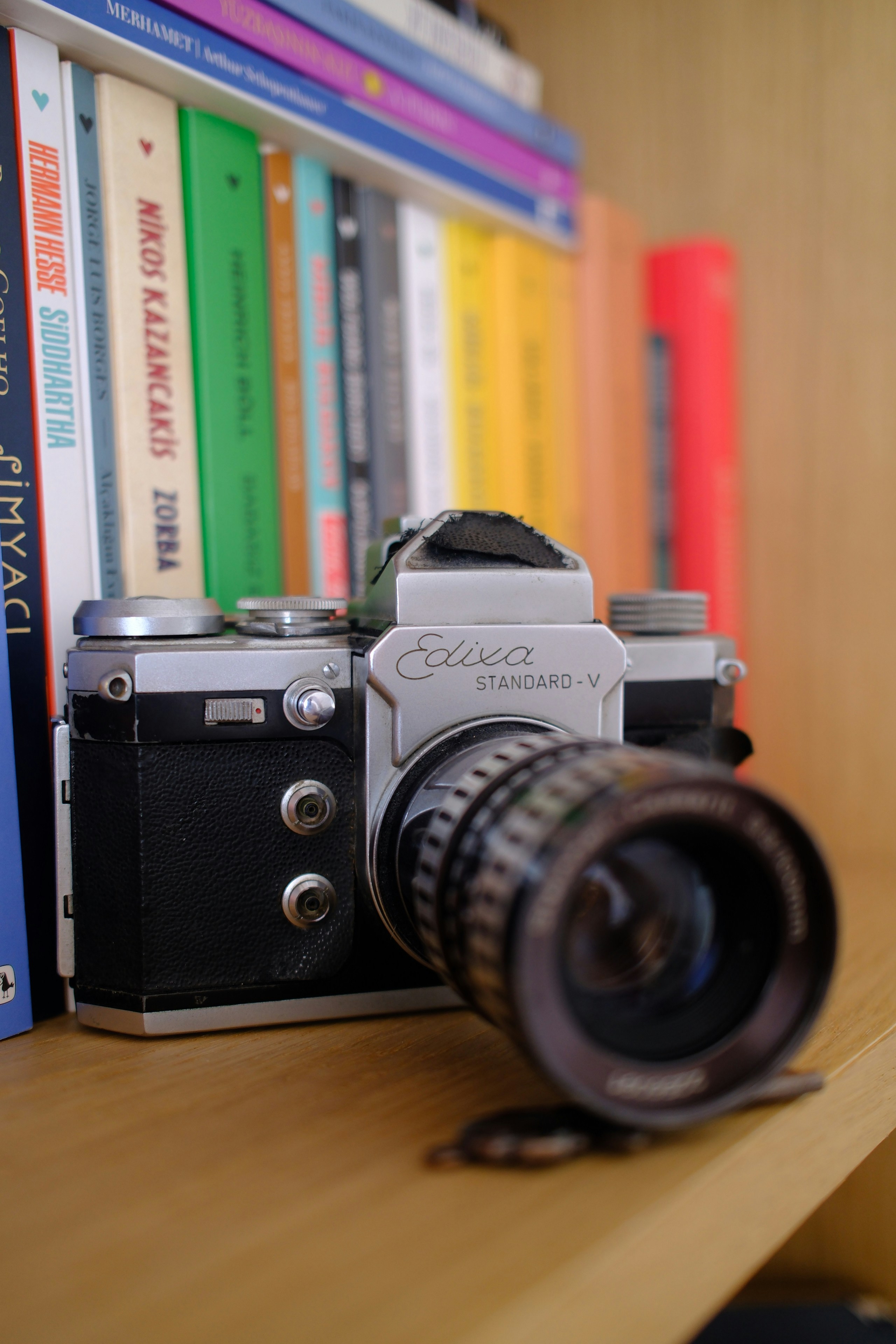 Vintage lens, modern gaze: a celebrated SLR resting among library spines