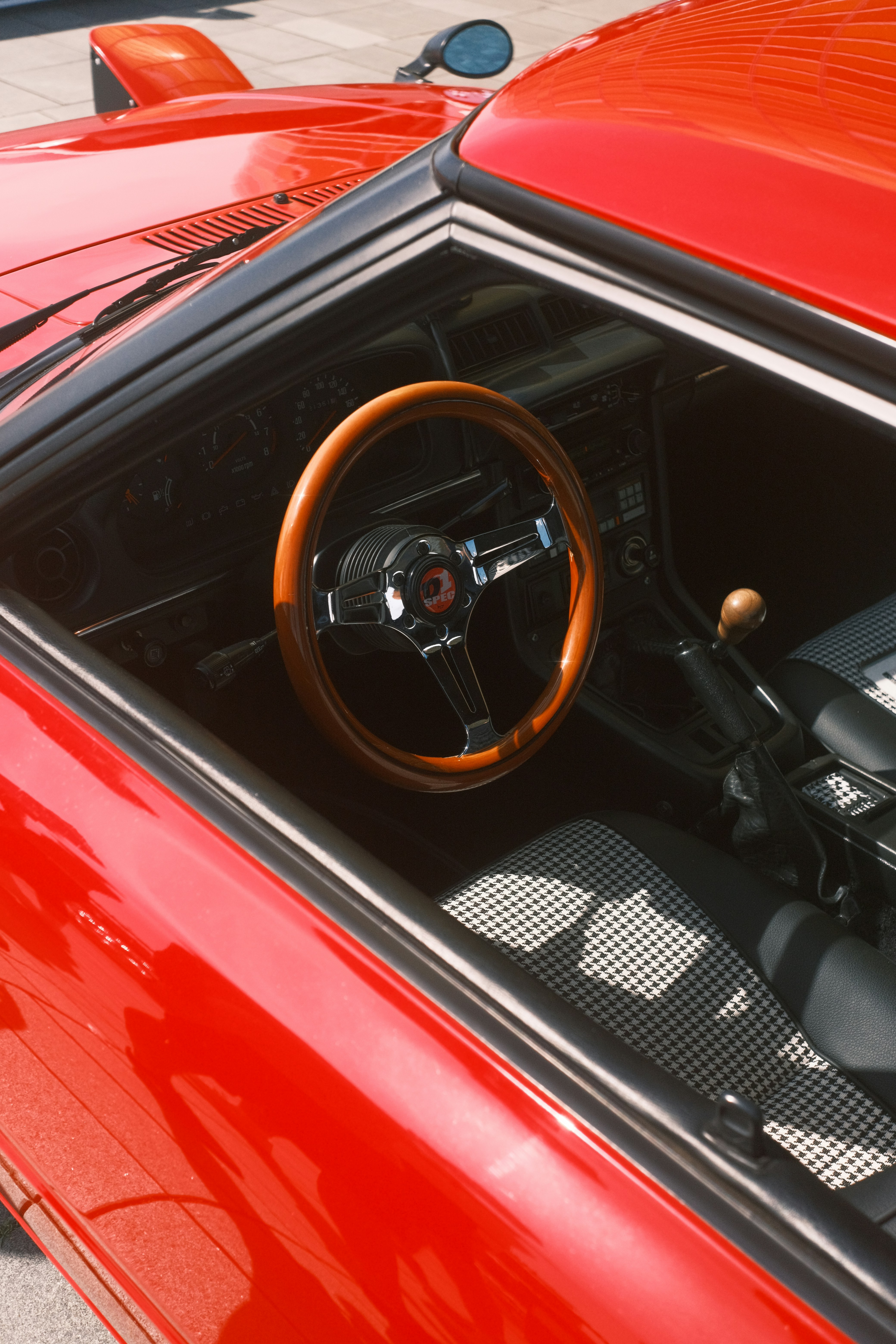 Red cockpit: classic sportscar interior with wooden wheel and houndstooth seats