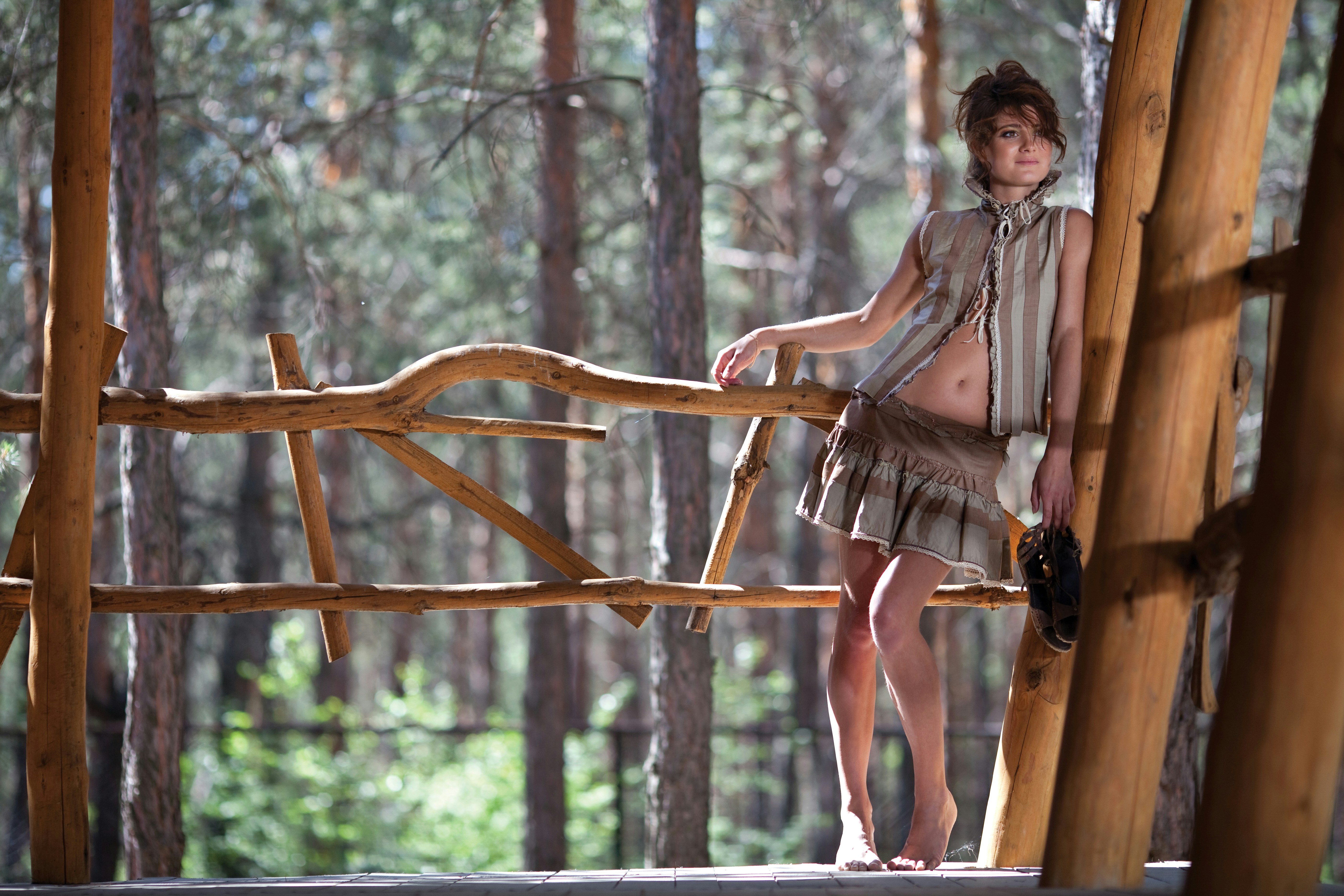 Girl on a rustic balcony in a sunlit forest