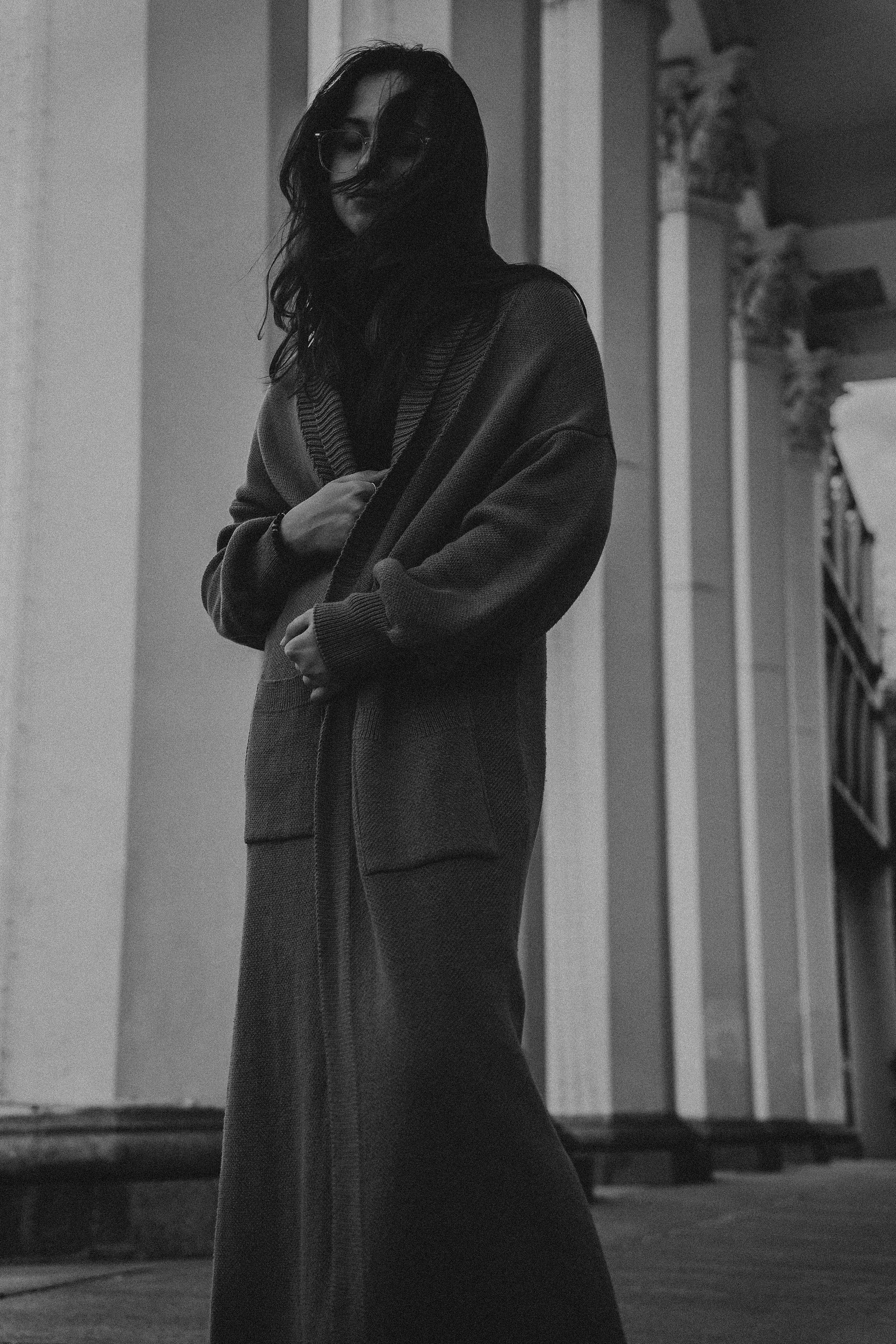 Coat-wrapped Solitude in Shadowed Columns