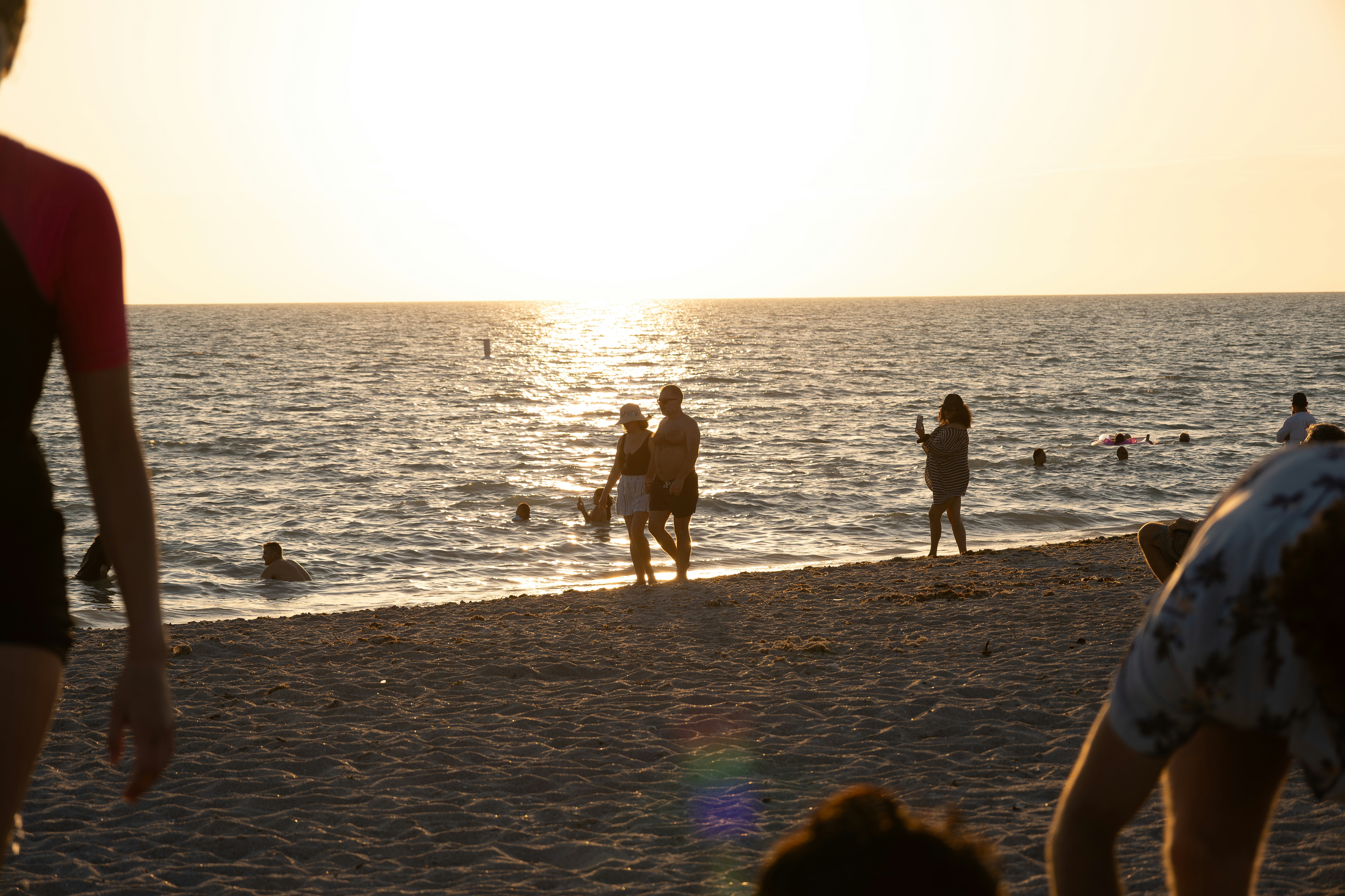 Sunlit Beach Silhouette: Couples by the Shore at Dusk