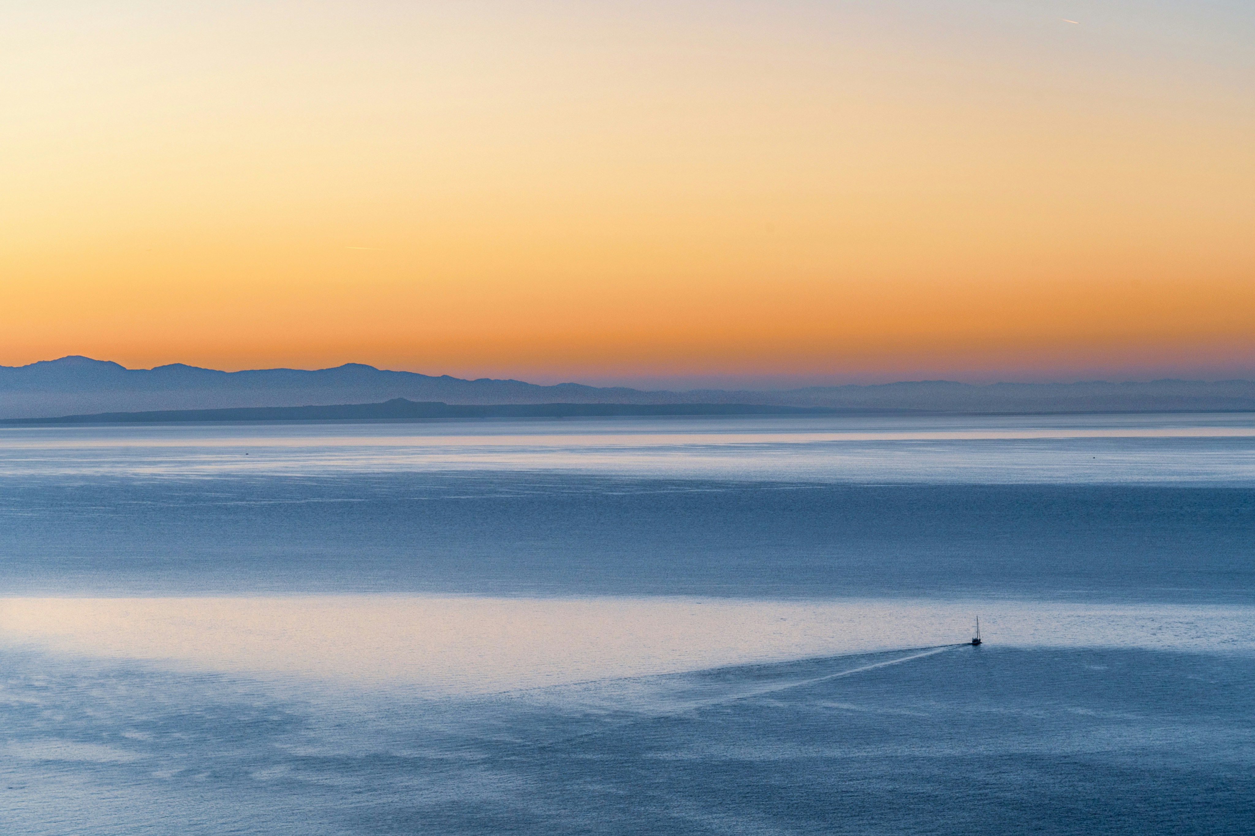 Dawn Over the Quiet Sea: Terraced Haze and a Lone Beacon