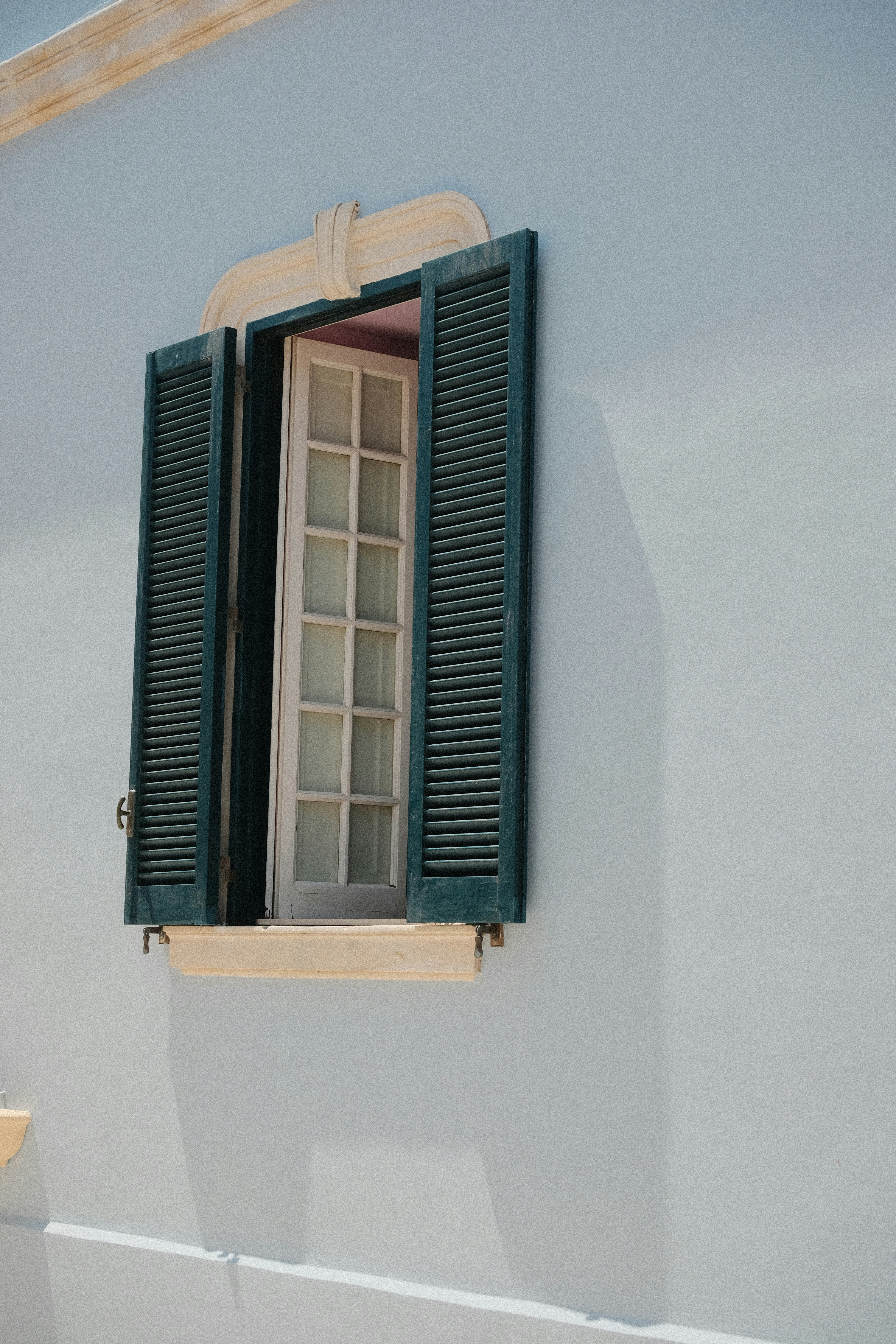 Teal Shuttered Window on Pale Blue Wall