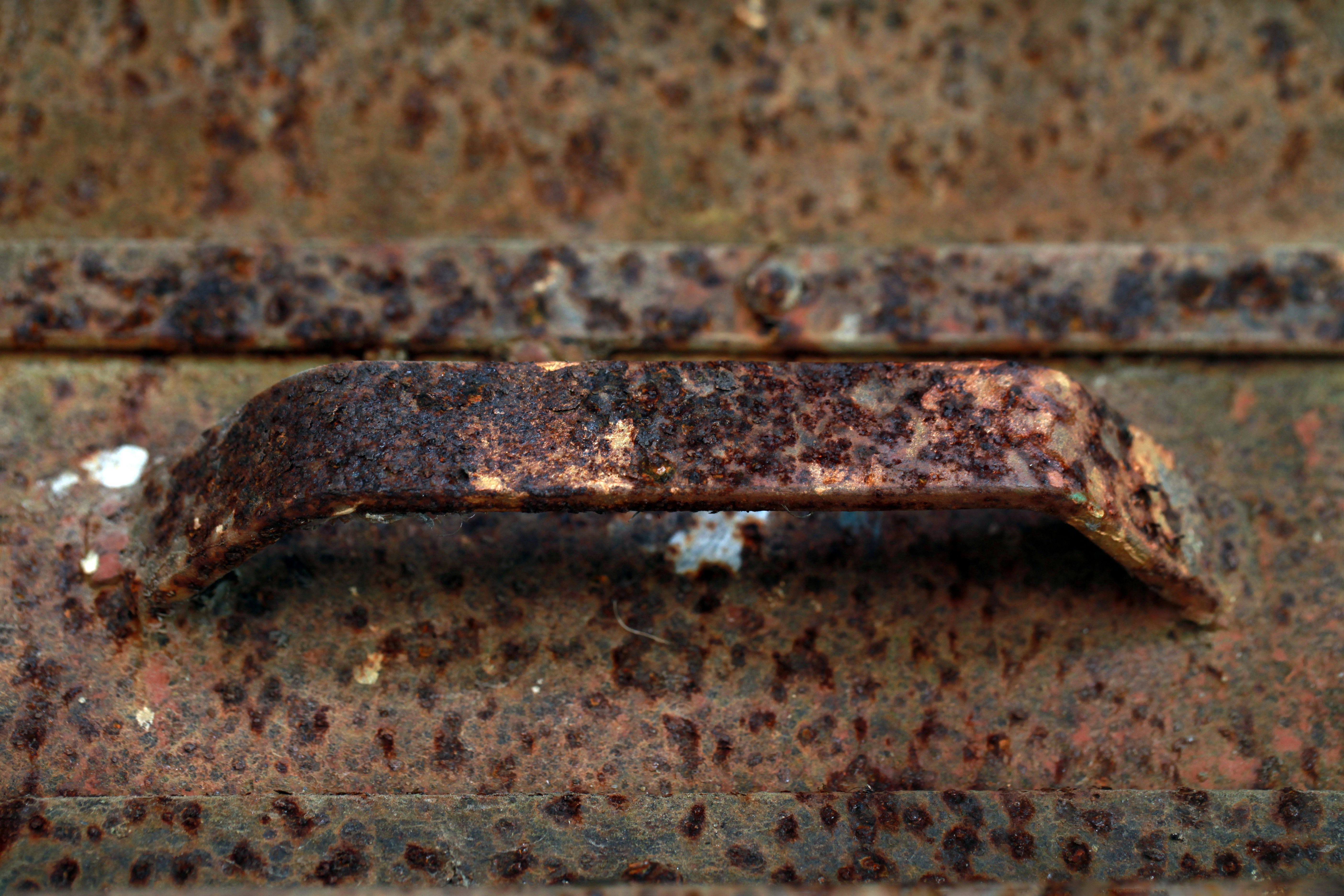 Rusted metal handle carved by time on a corroded surface