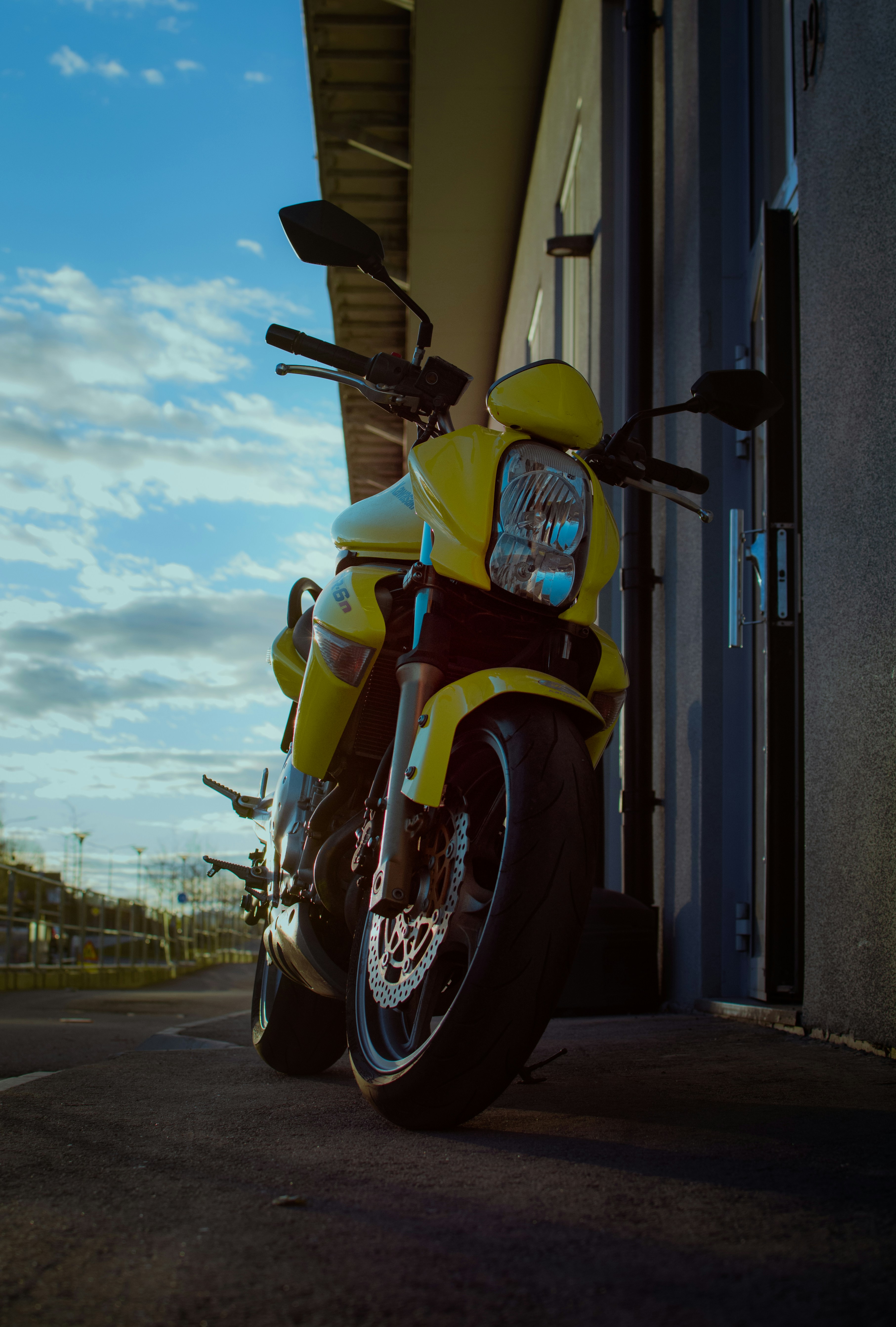 Yellow sport motorcycle resting outside a building with a blue door, angular headlamp and modern urban setting.