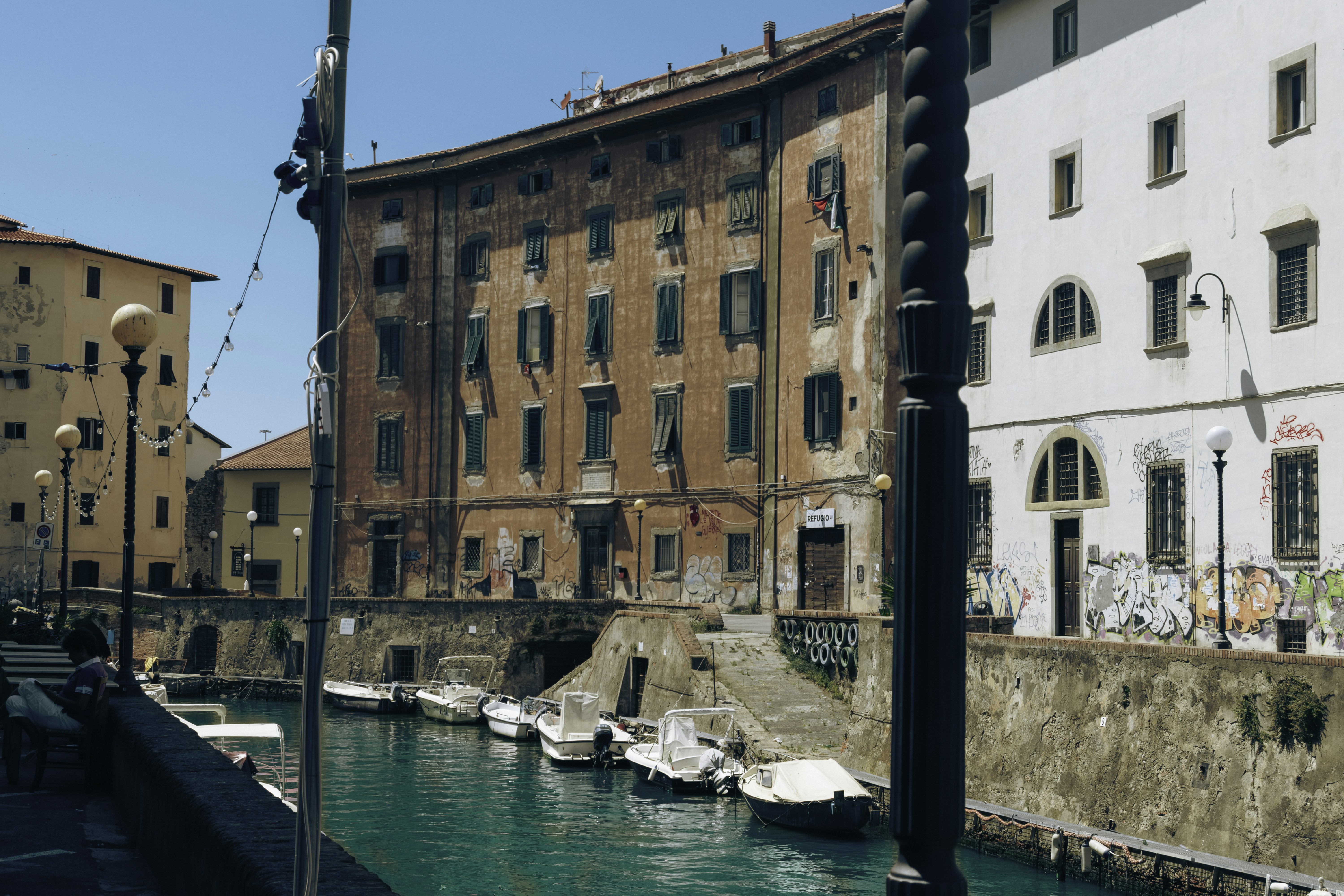 Canal Edge Portrait: A Sunlit Italian Waterway framed by weathered brick and white stucco