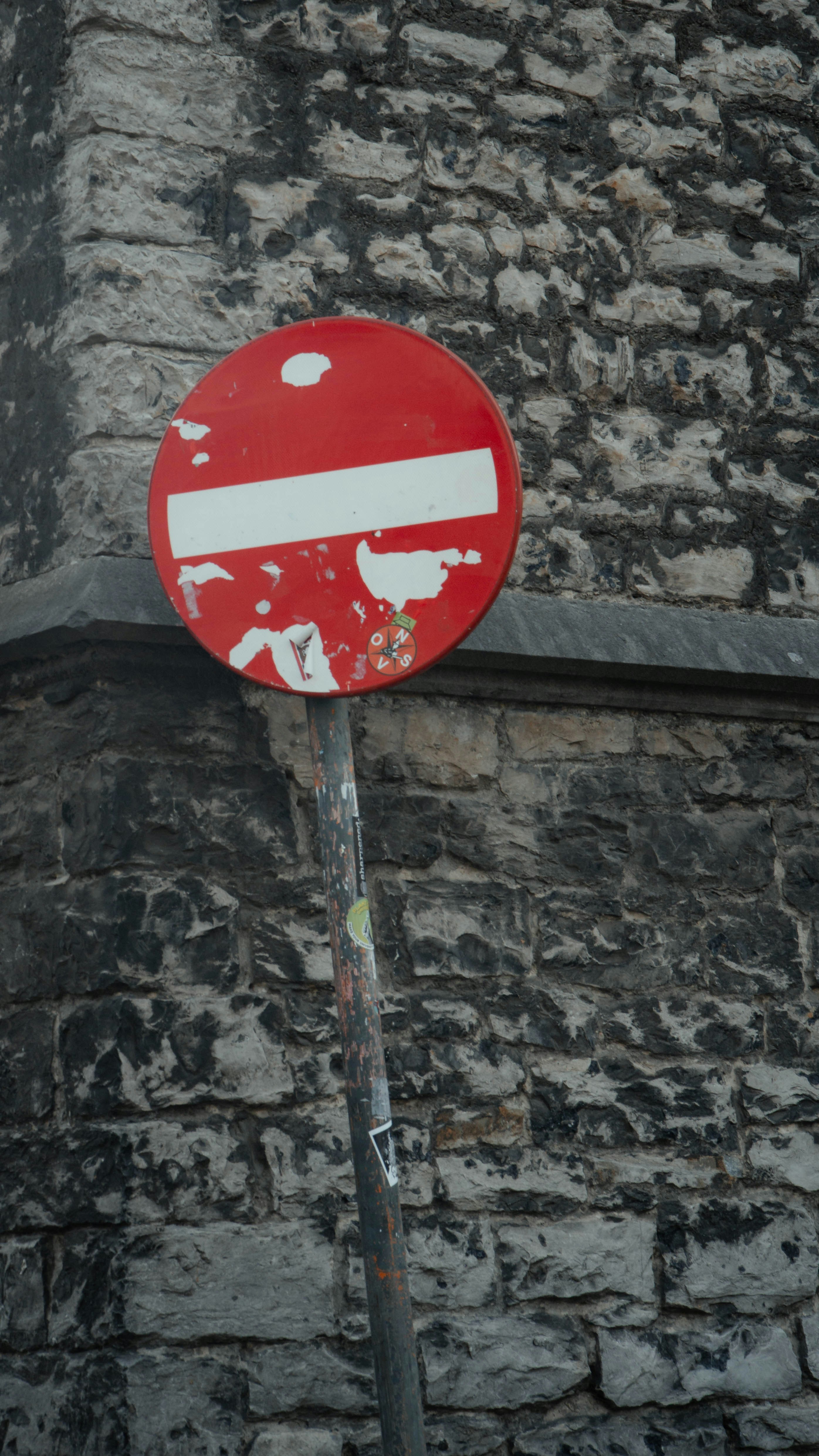 Red Barred: A Weathered No-Entry Sign Leans Against A Stone Wall