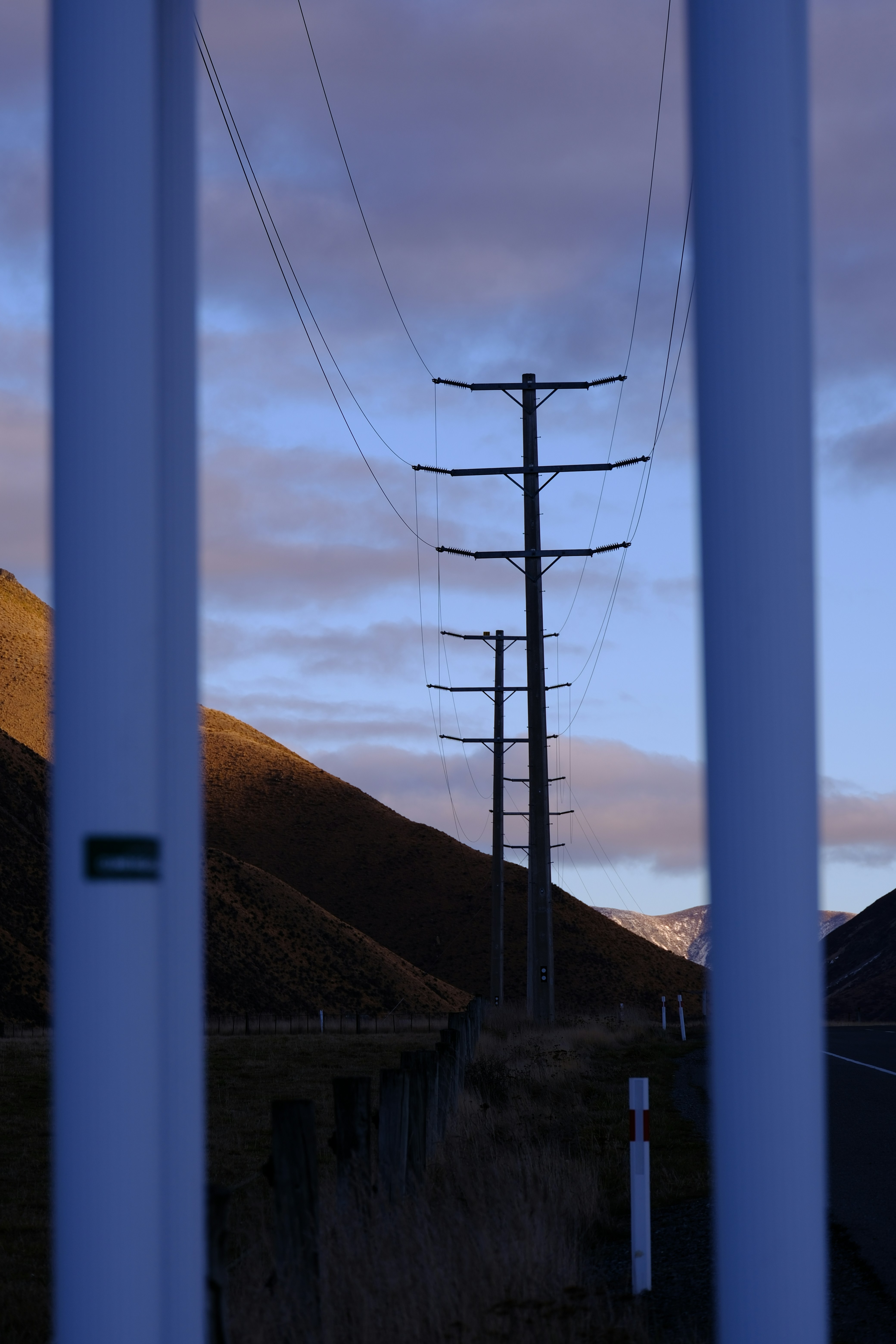 Threads of Silence: Power Lines Vanishing into a Dusked Valley