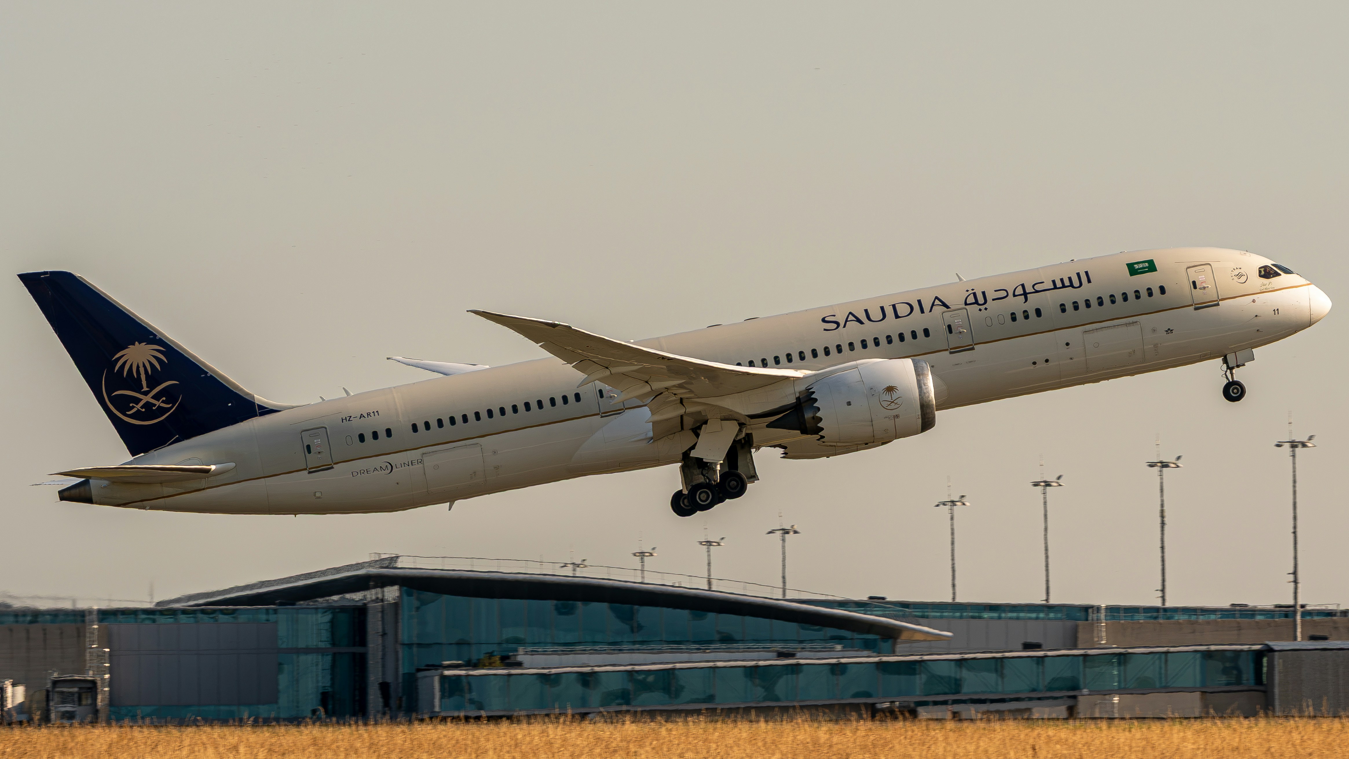 A saudia airplane takes off from an airport runway.