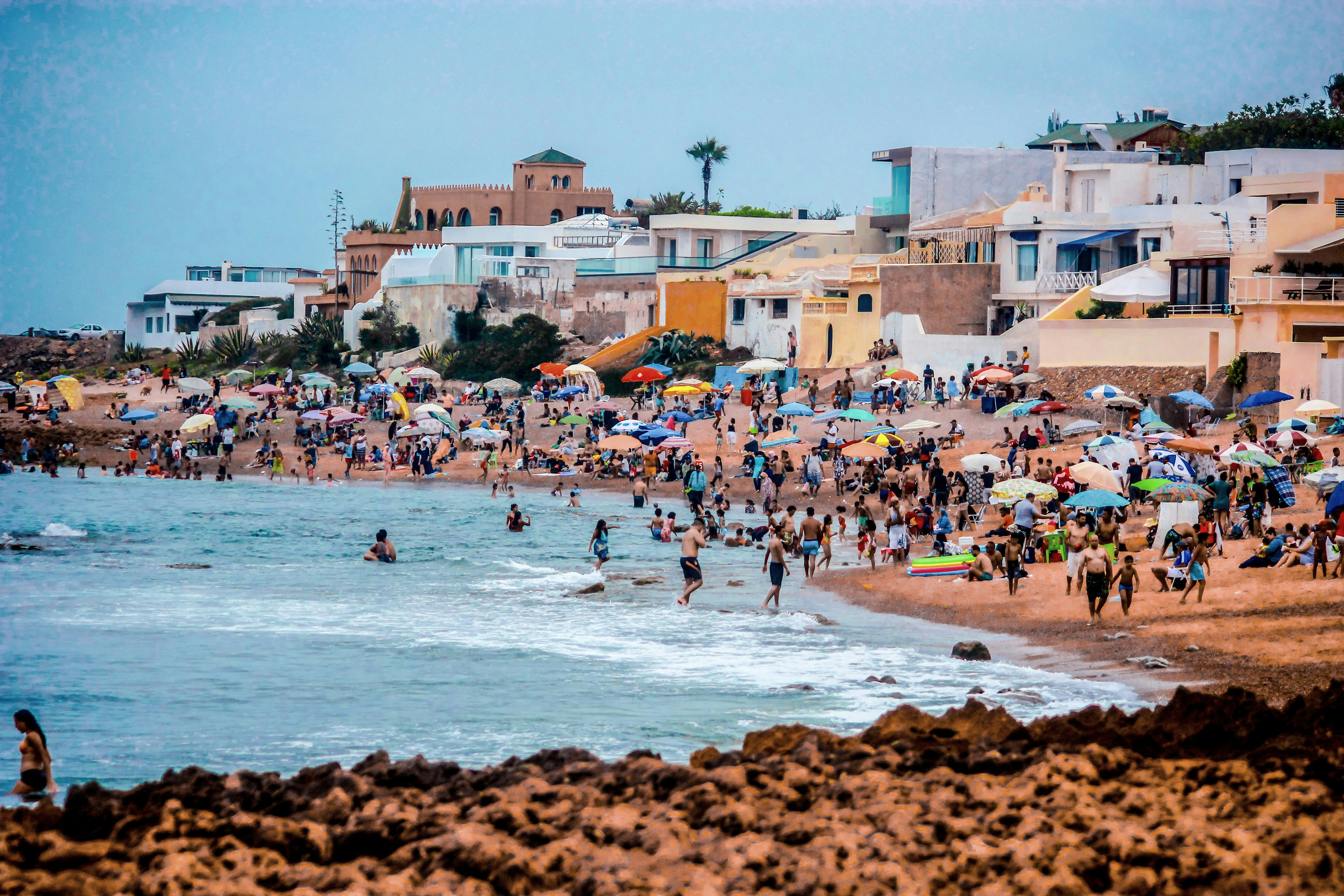 Sunlit Shoreline: A Bustling Beachfront Scene with Colorful Umbrellas