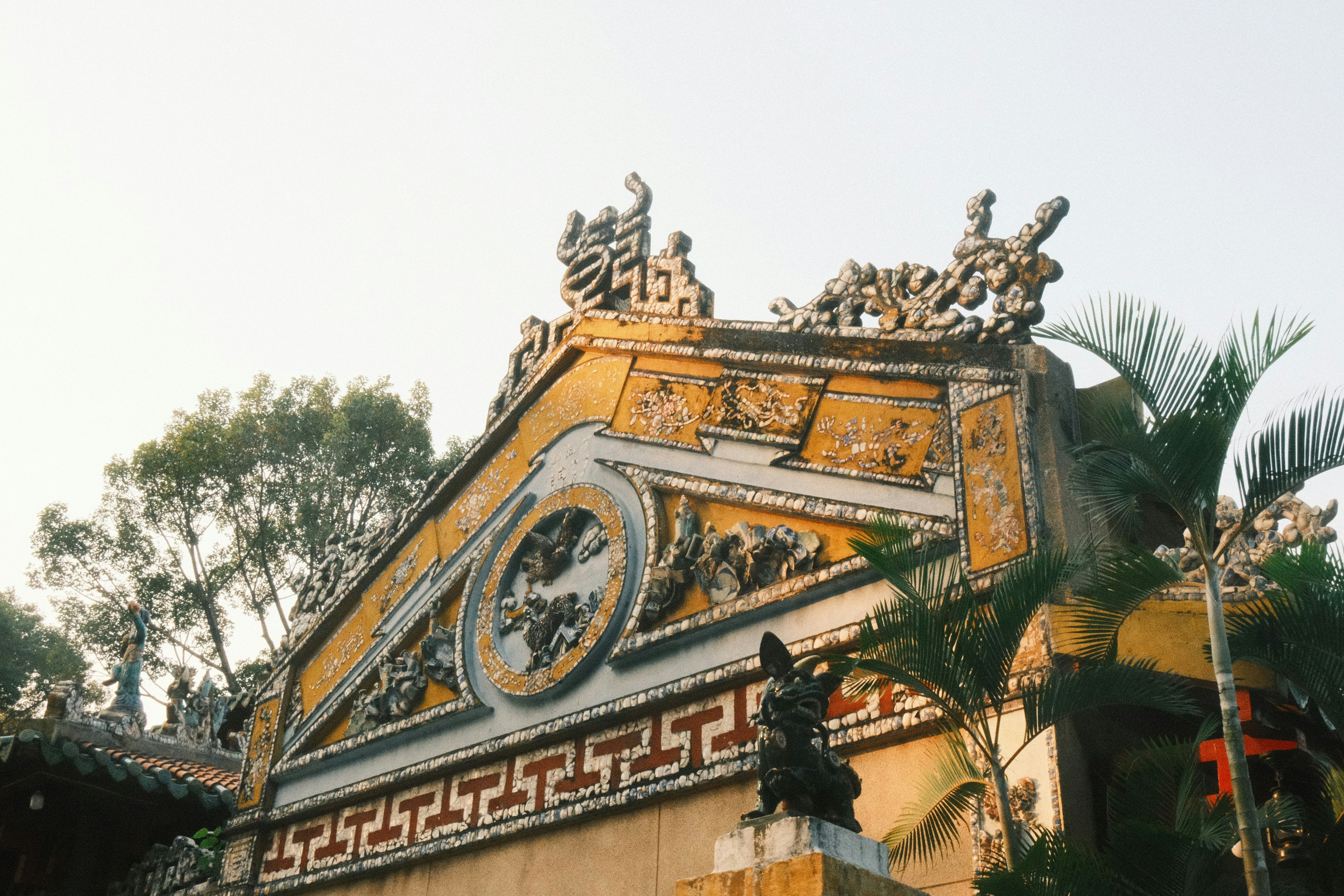 Ornate temple façade crowned with sculpted figures under a pale morning sky