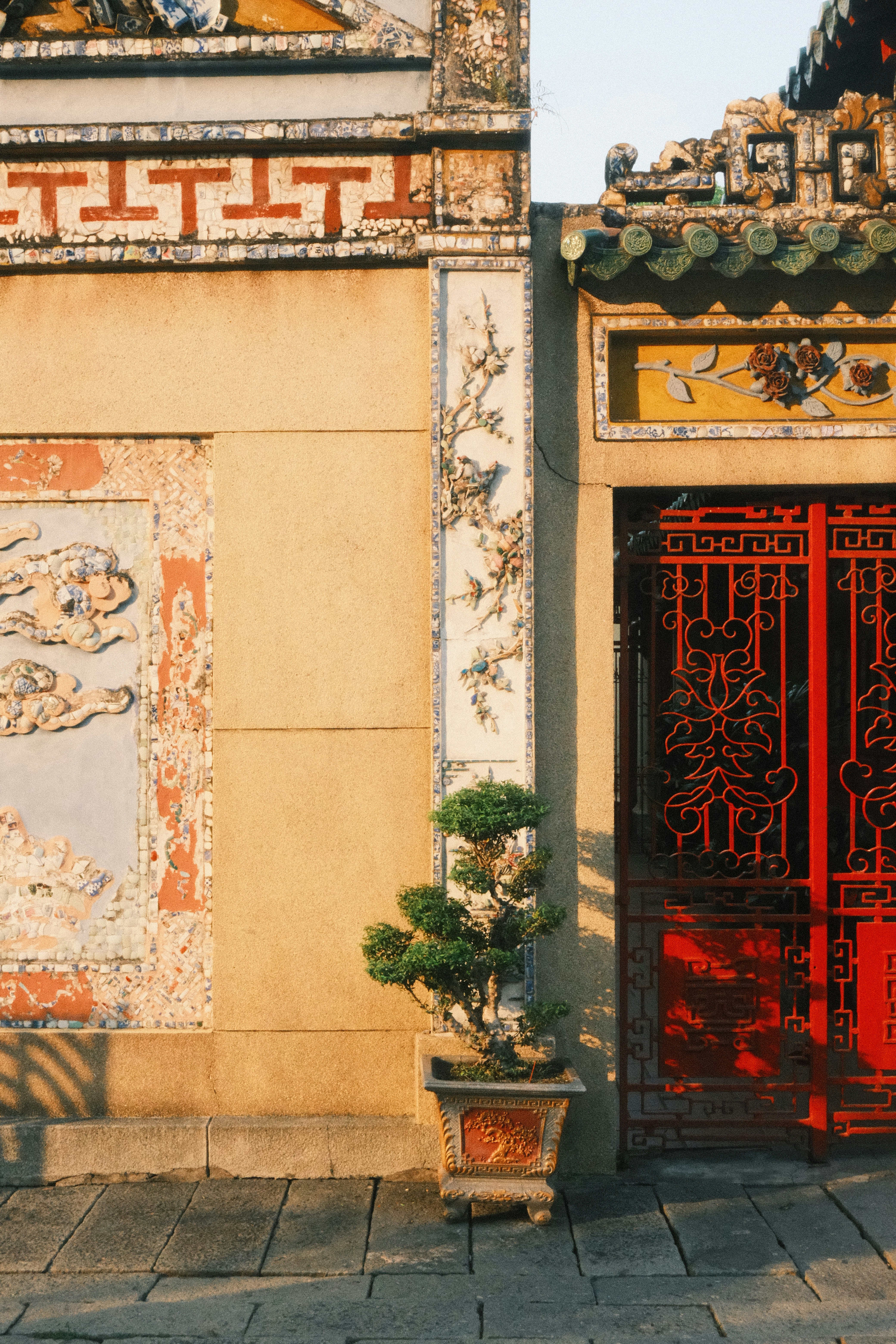 Red Gate and Bonsai in Sunlit Courtyard