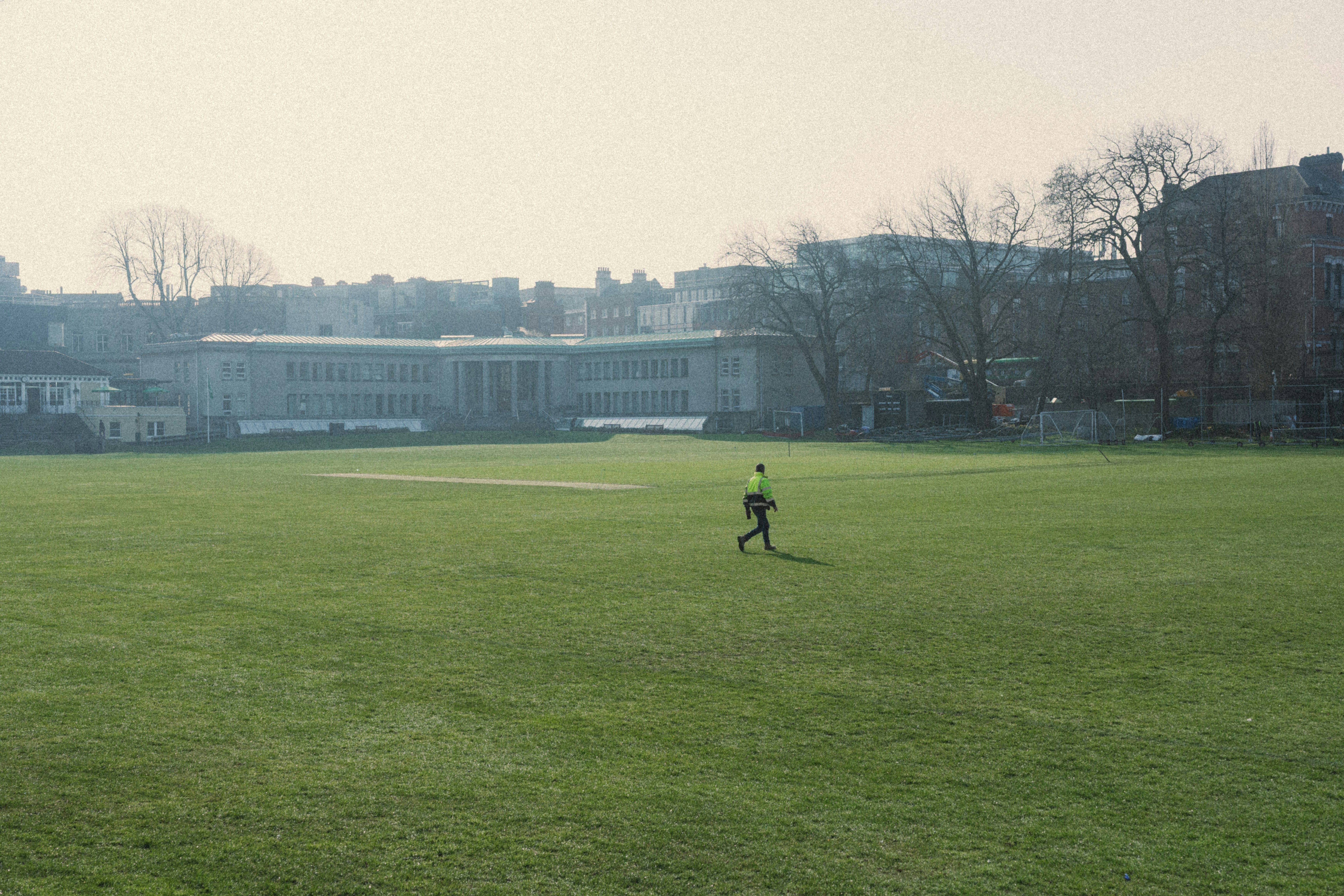 Solo Runner Across an Expansive Park Under Pale Sky