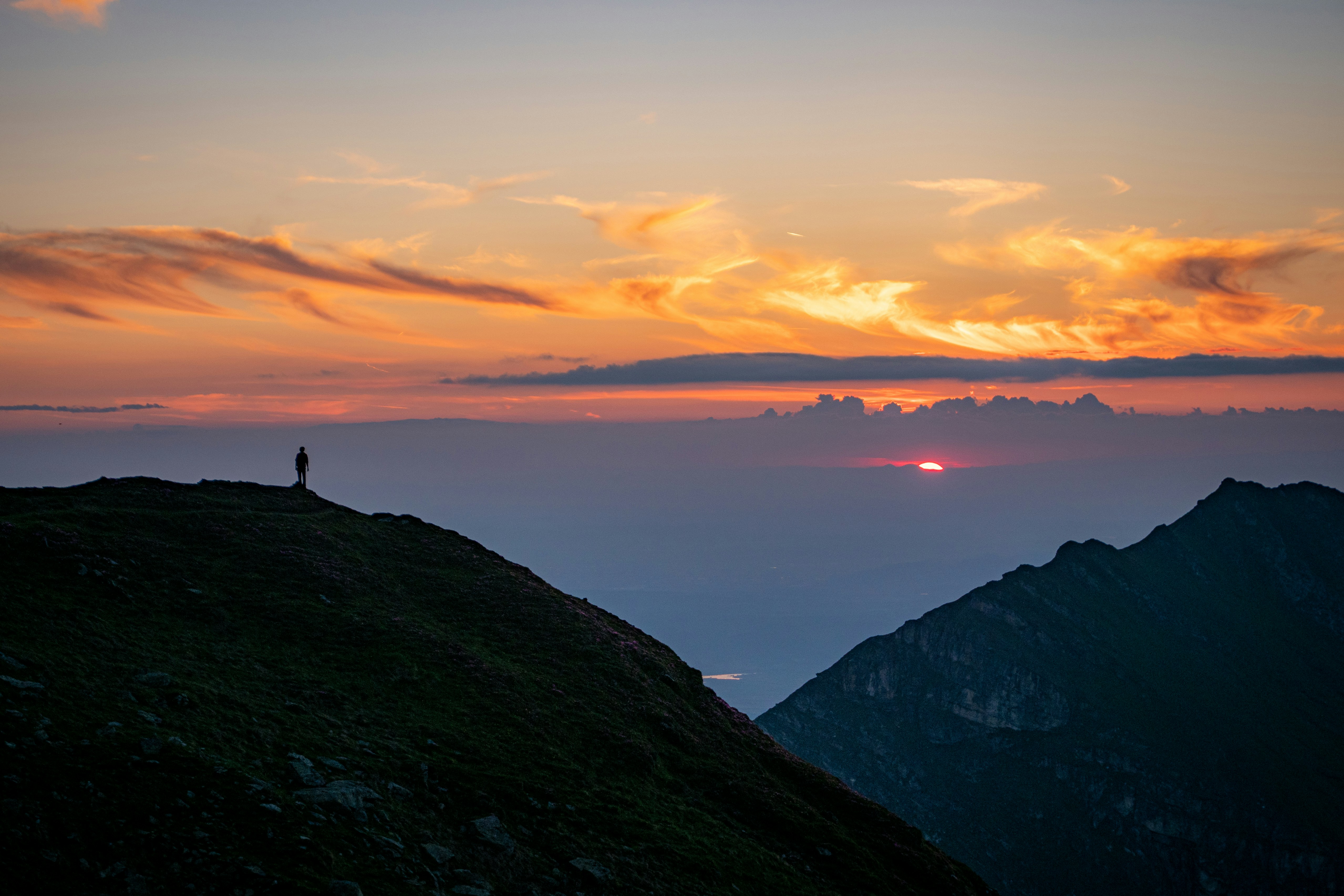Silhouette at Sunrise: A lone figure on a ridge watching the sun kiss the horizon