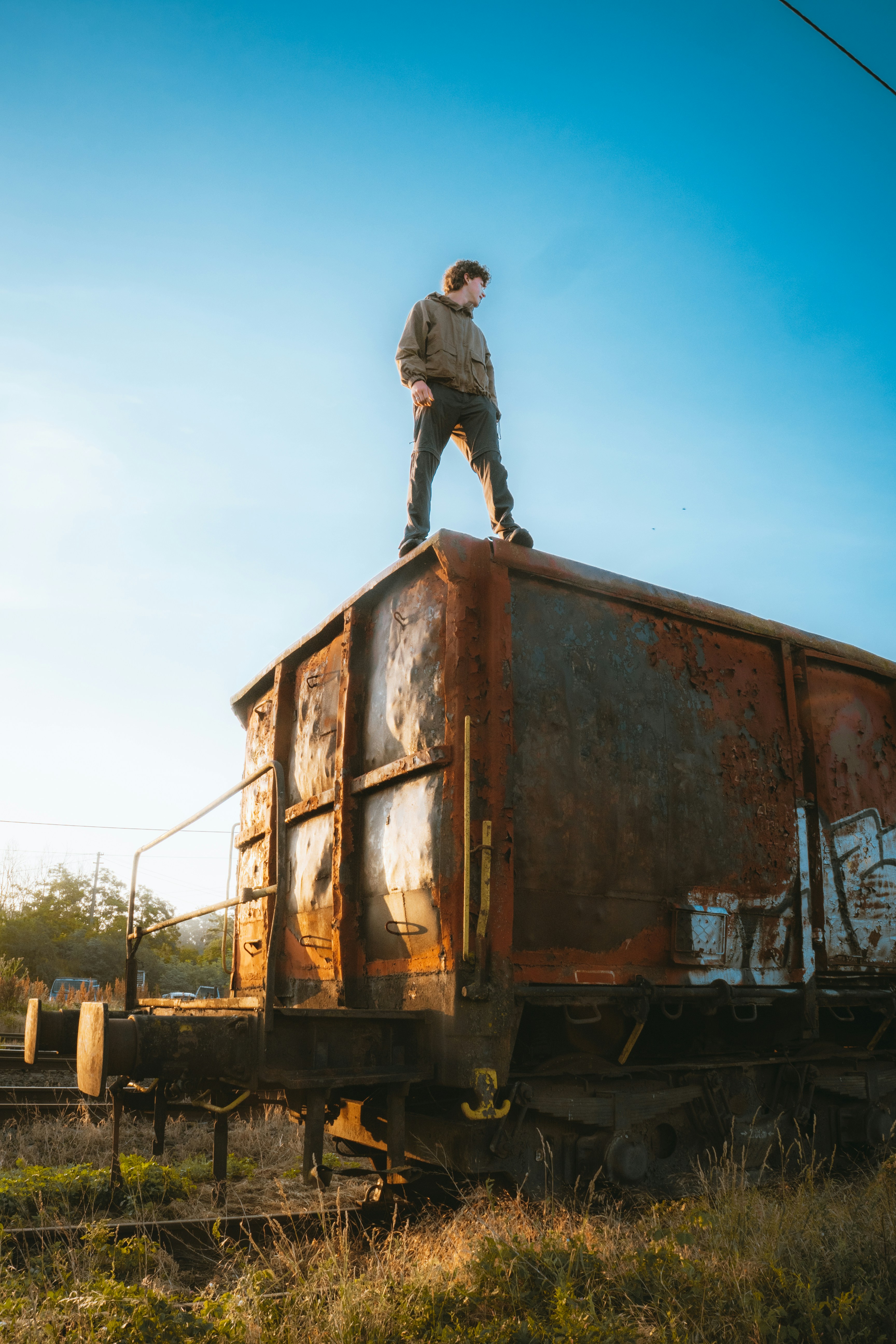  atop rusted train car: a lone climber commands the scene against a clear blue sky