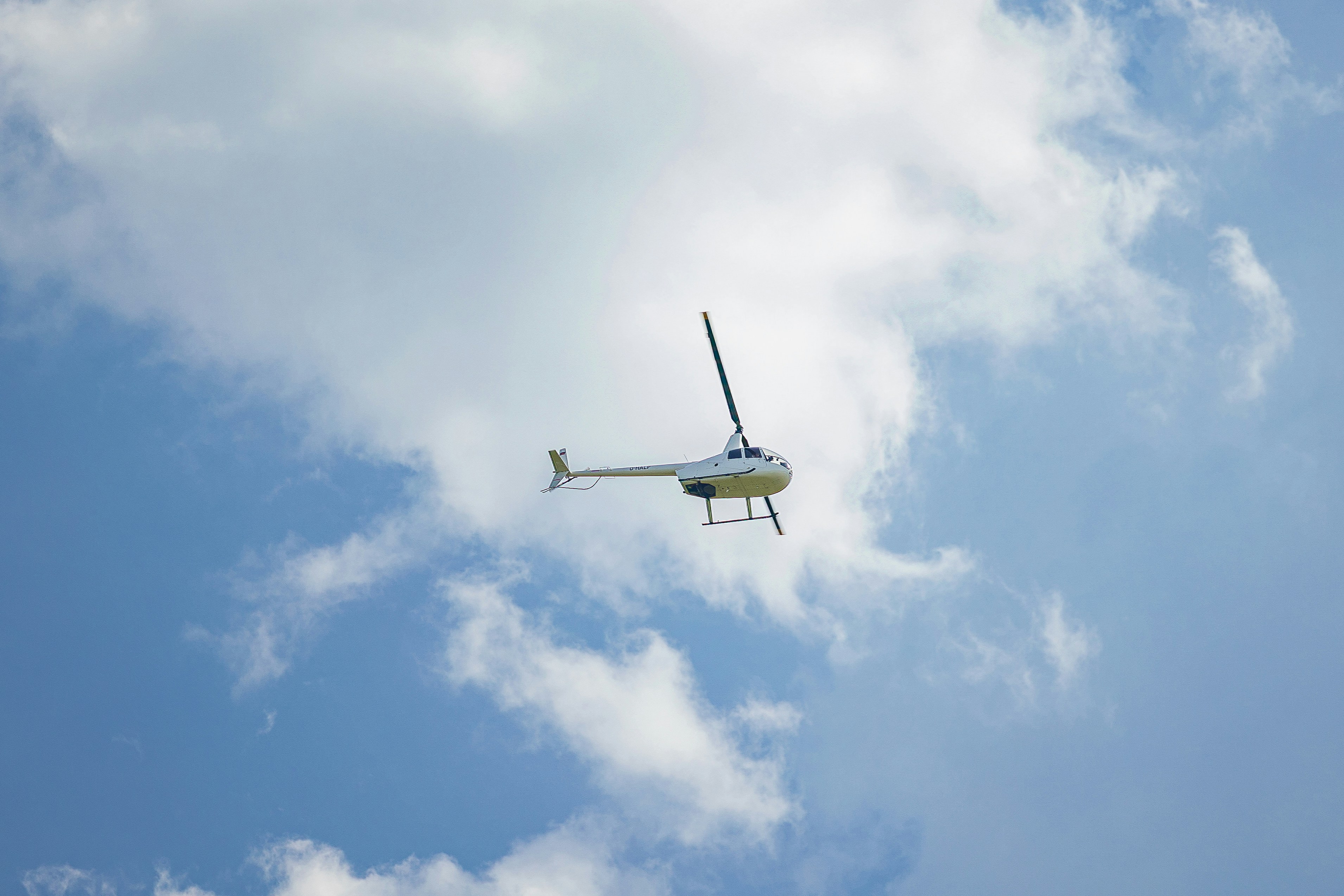 A lone helicopter glides through a bright afternoon sky