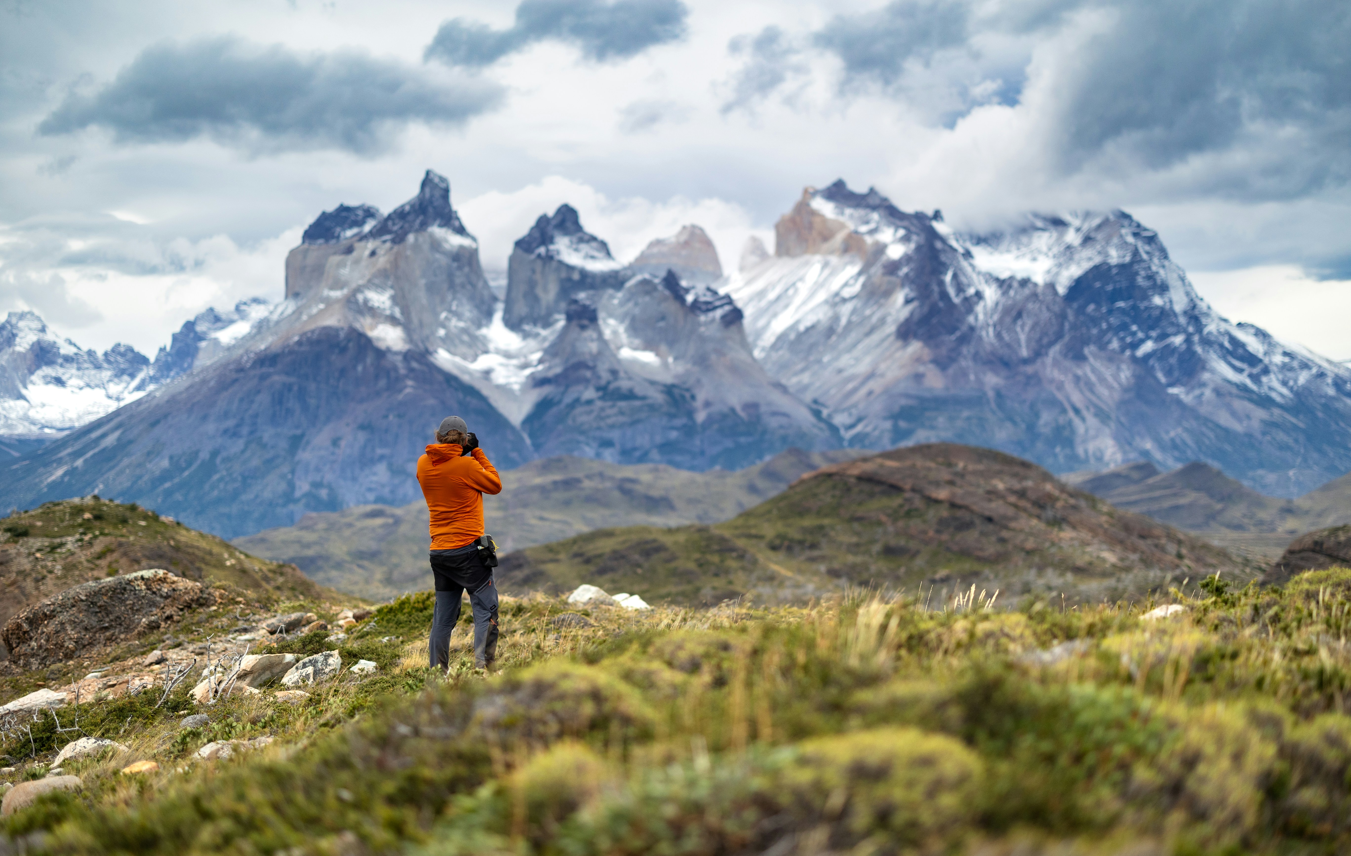 Orange-clad Photographer Amid Mountain Expanse
