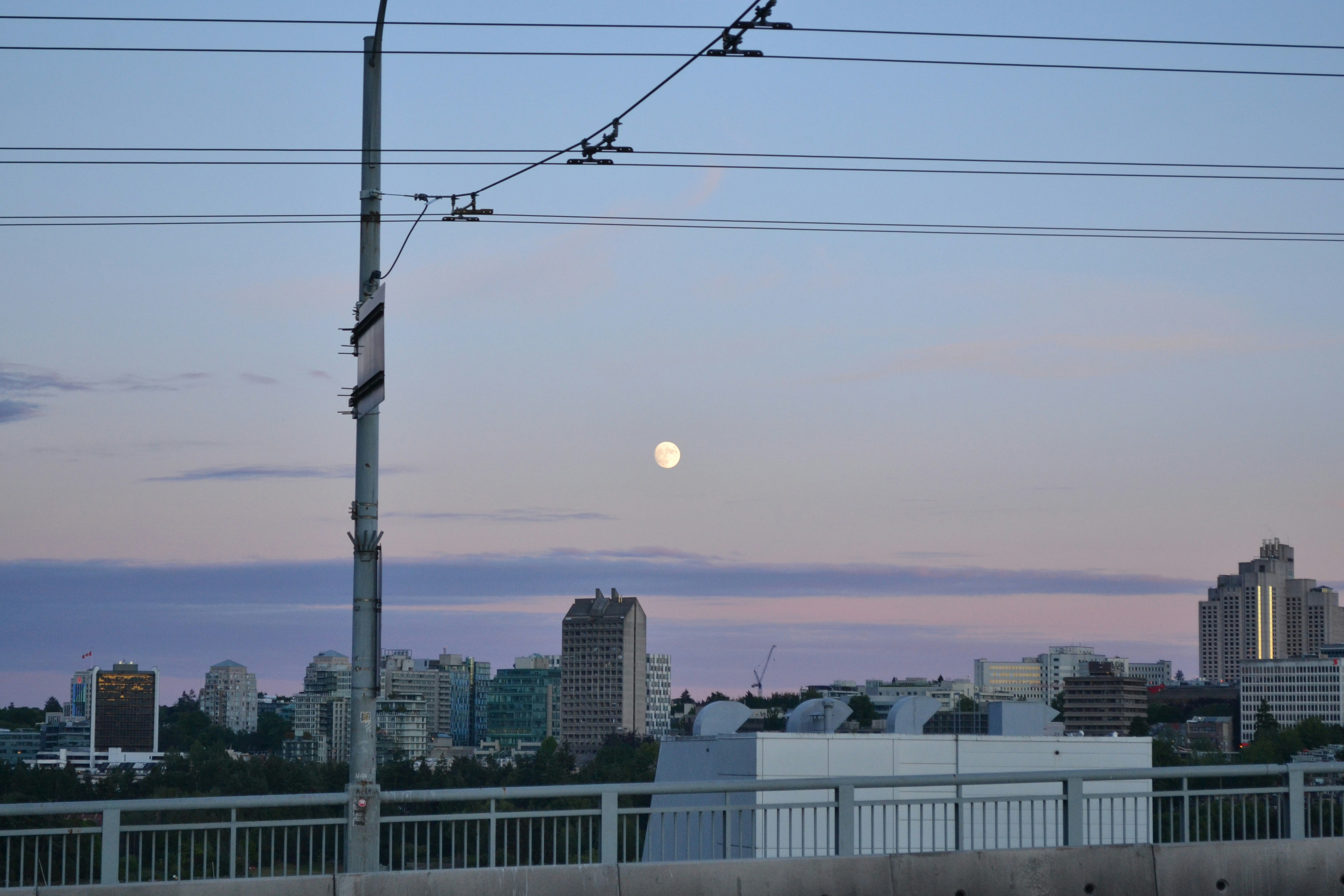 Moonrise over the city from a rooftop bridge