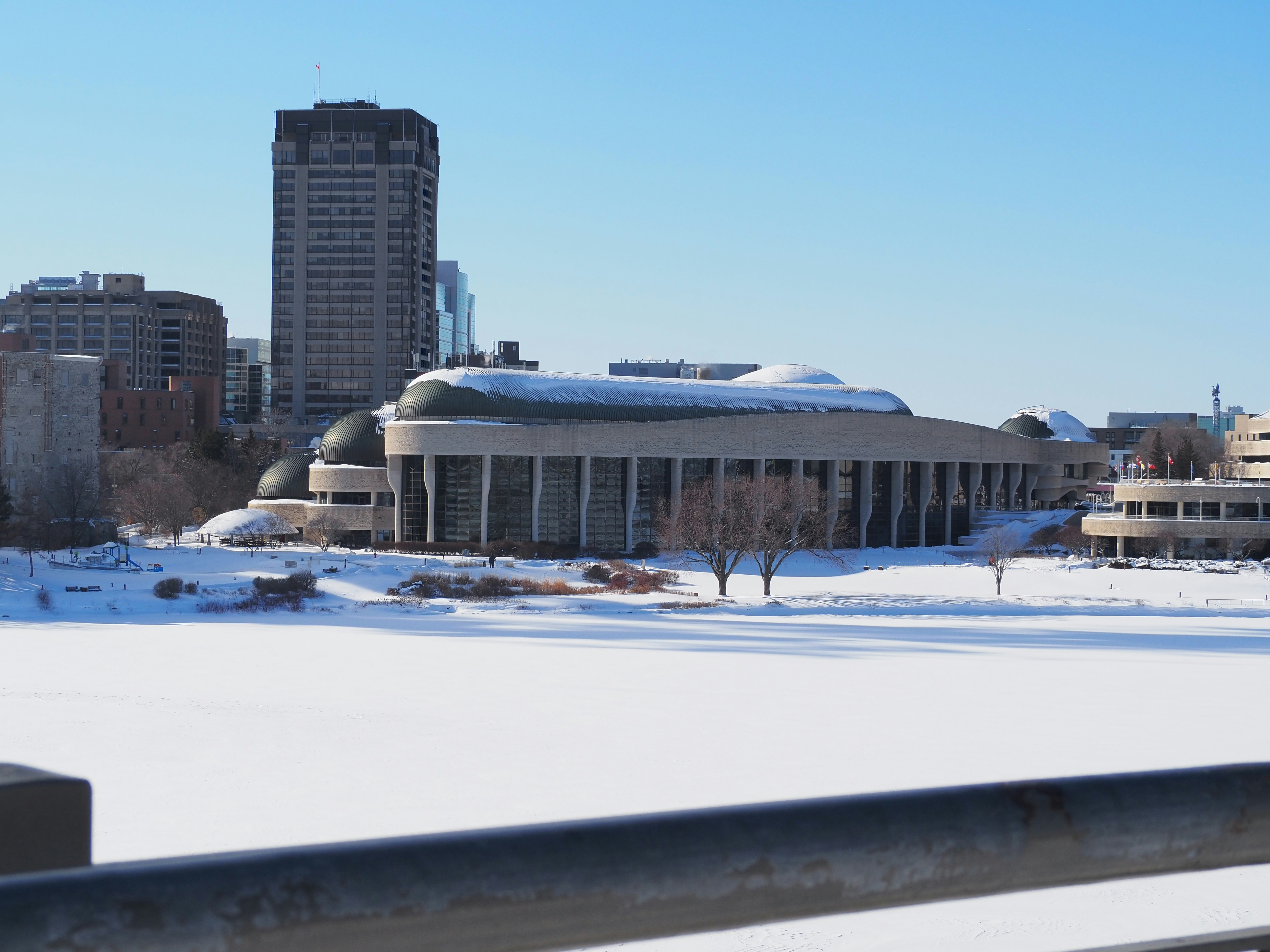 Snow-dented skyline and sculpted civic complex by a frozen river