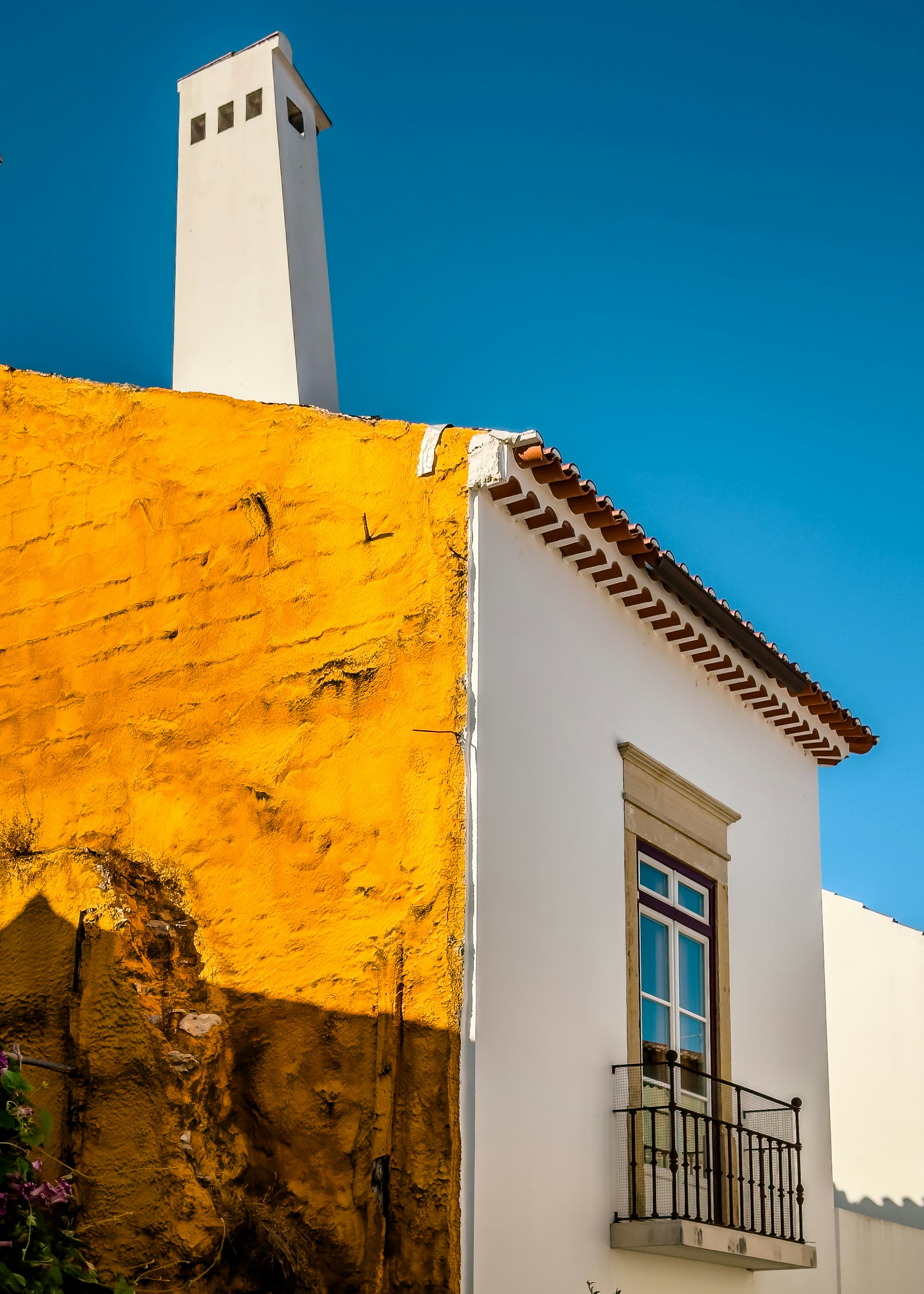 Sunlit Orange Wall Meets Cream Facade Under a Clear Blue Sky