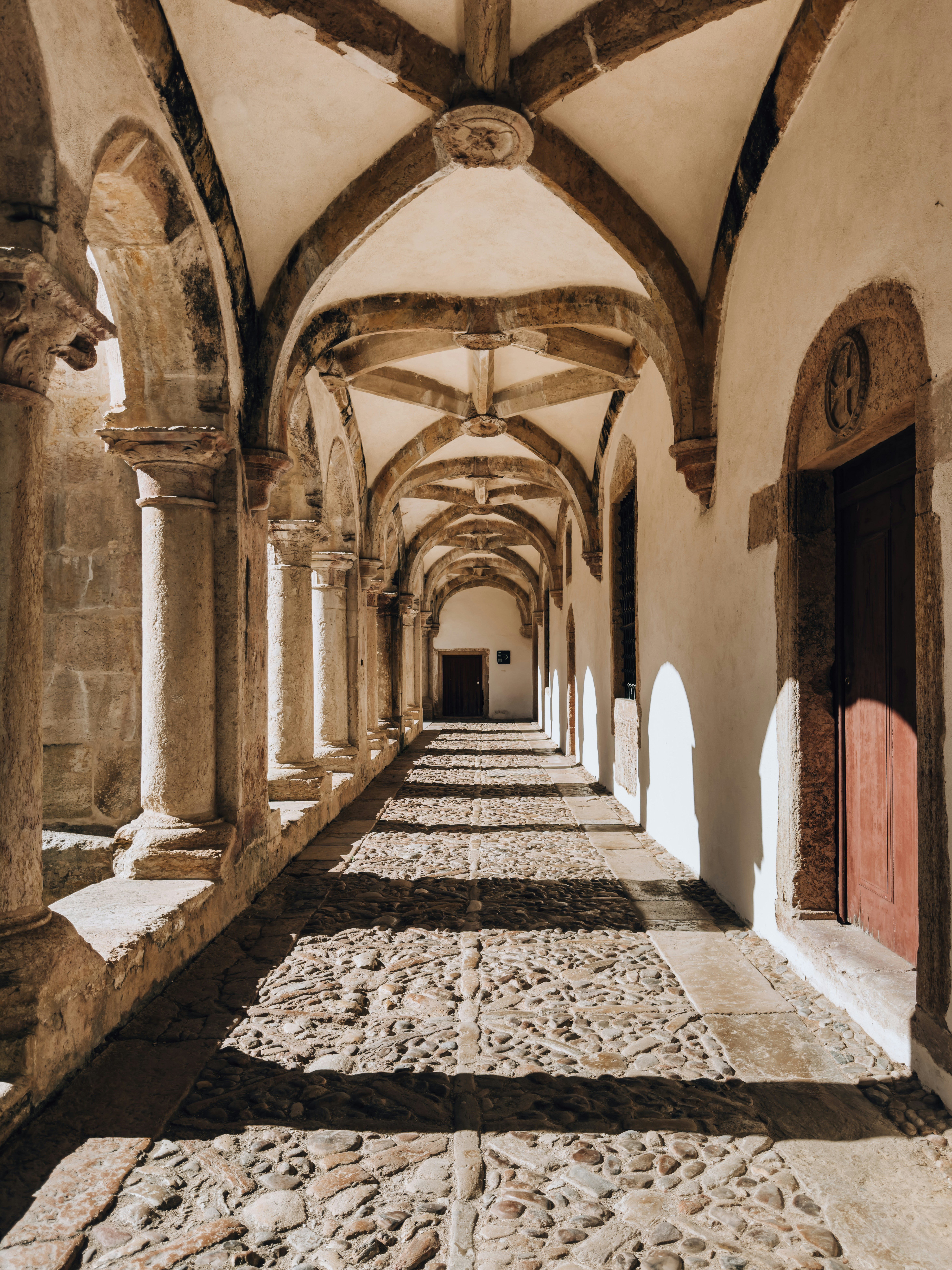 Arched Cloister Rays: Sunlit Corridor of Stone and Shadow