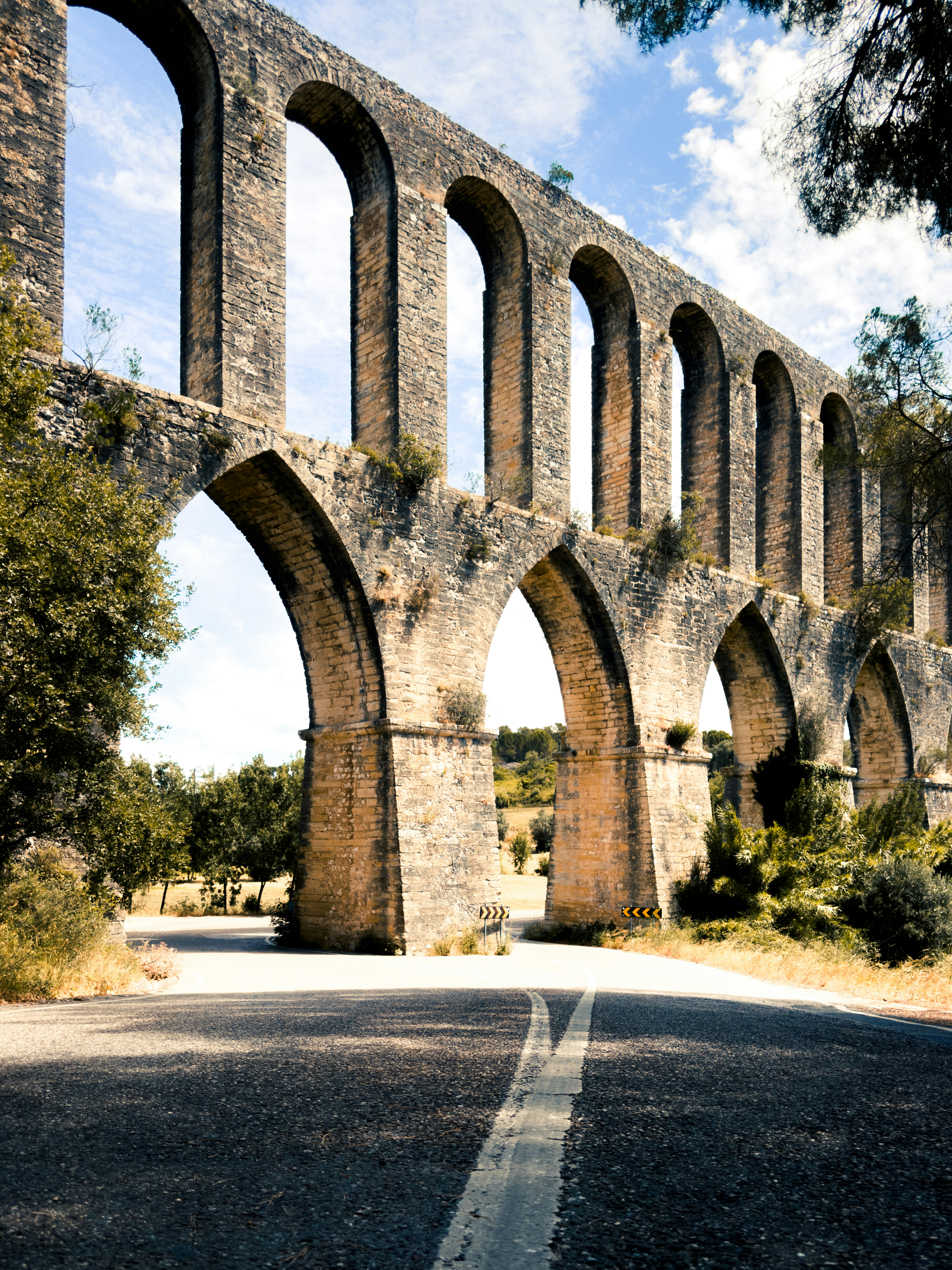 Ancient Aqueduct Arches Reach Across a Sunlit Road