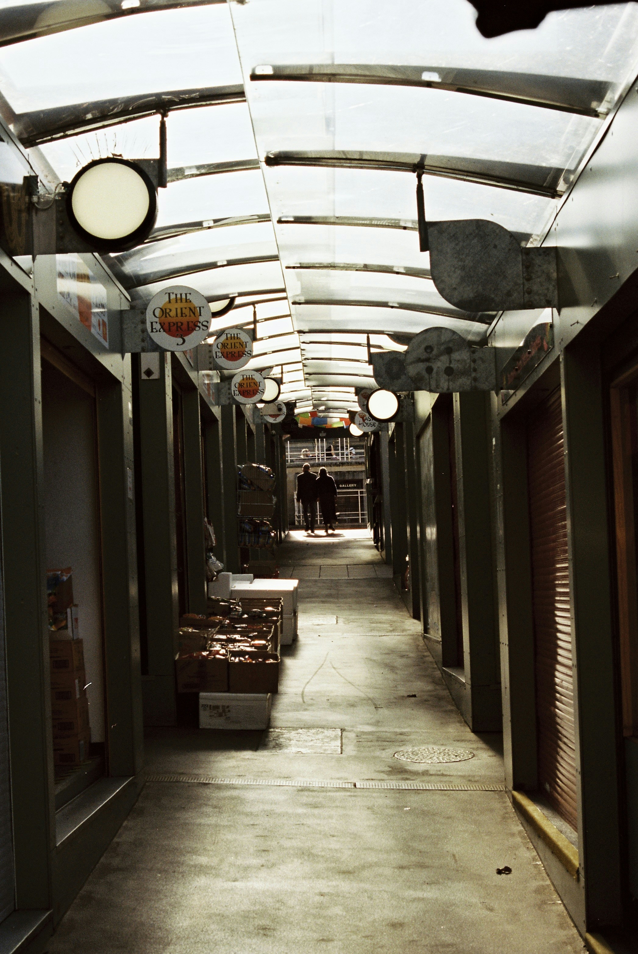 A Narrow Market Corridor Leads the Eye Toward the Distant Figures