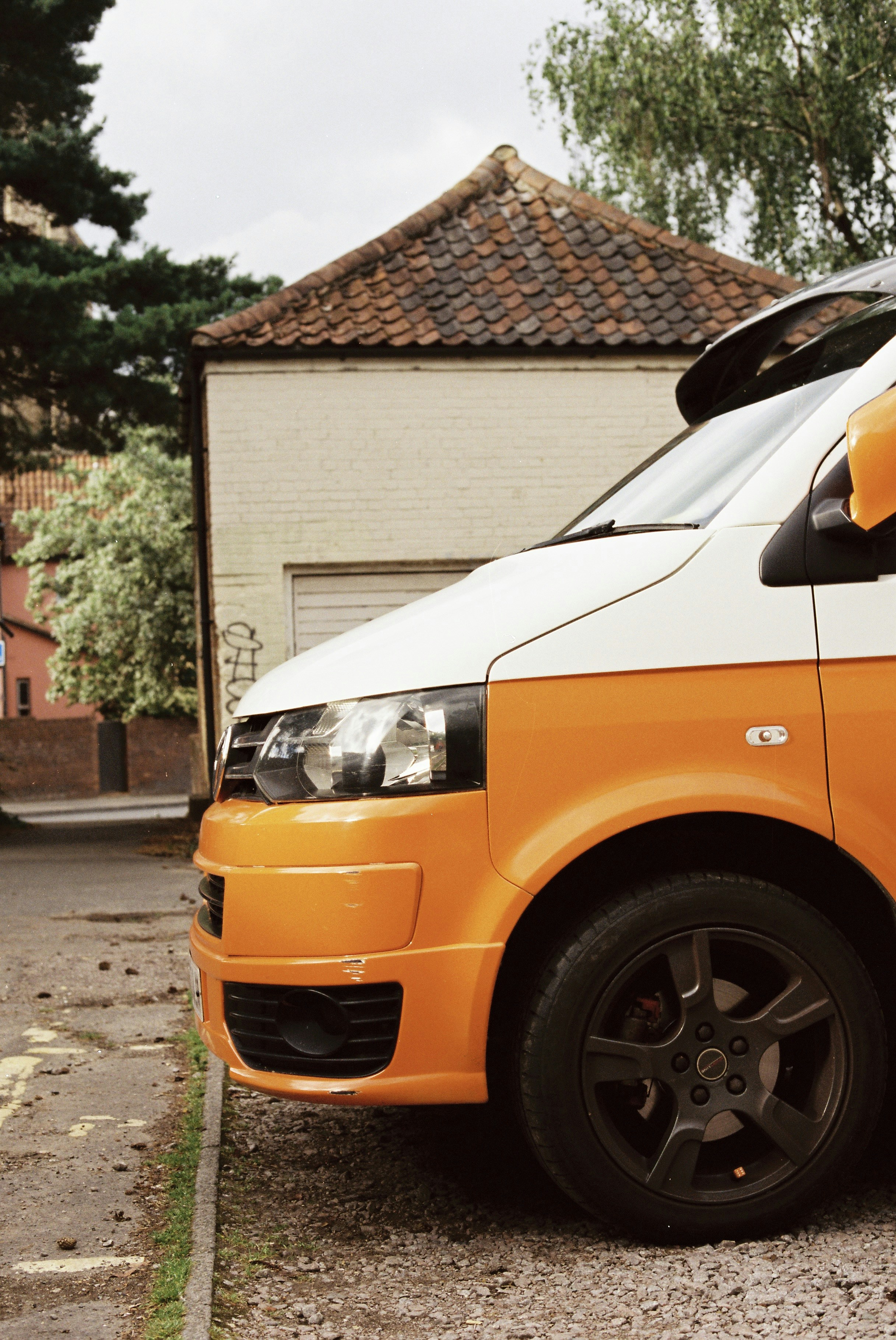 Front-Quarter of a Bright Orange Van Resting by a Quiet Street
