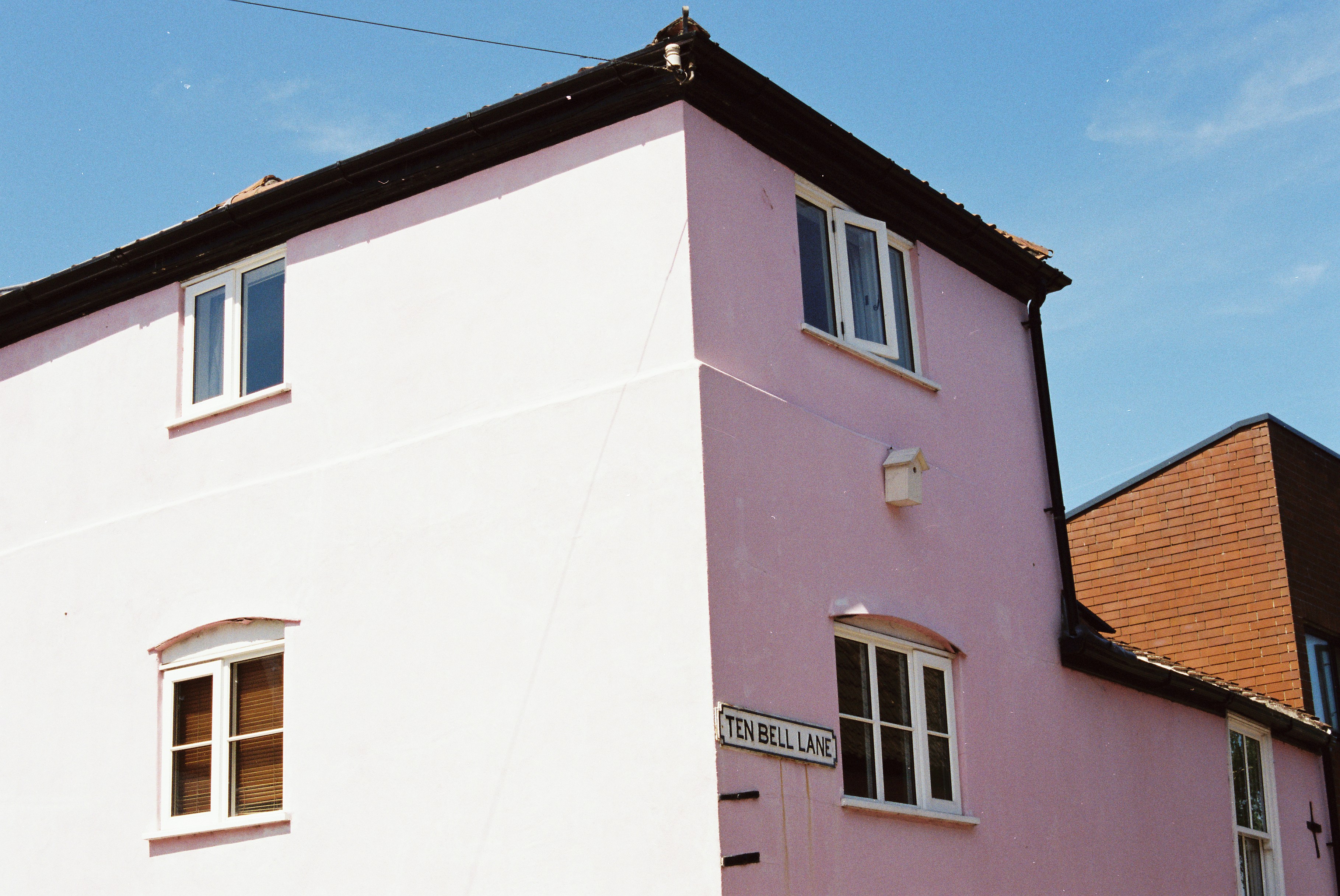 Sunlit pink townhouse corner under clear sky