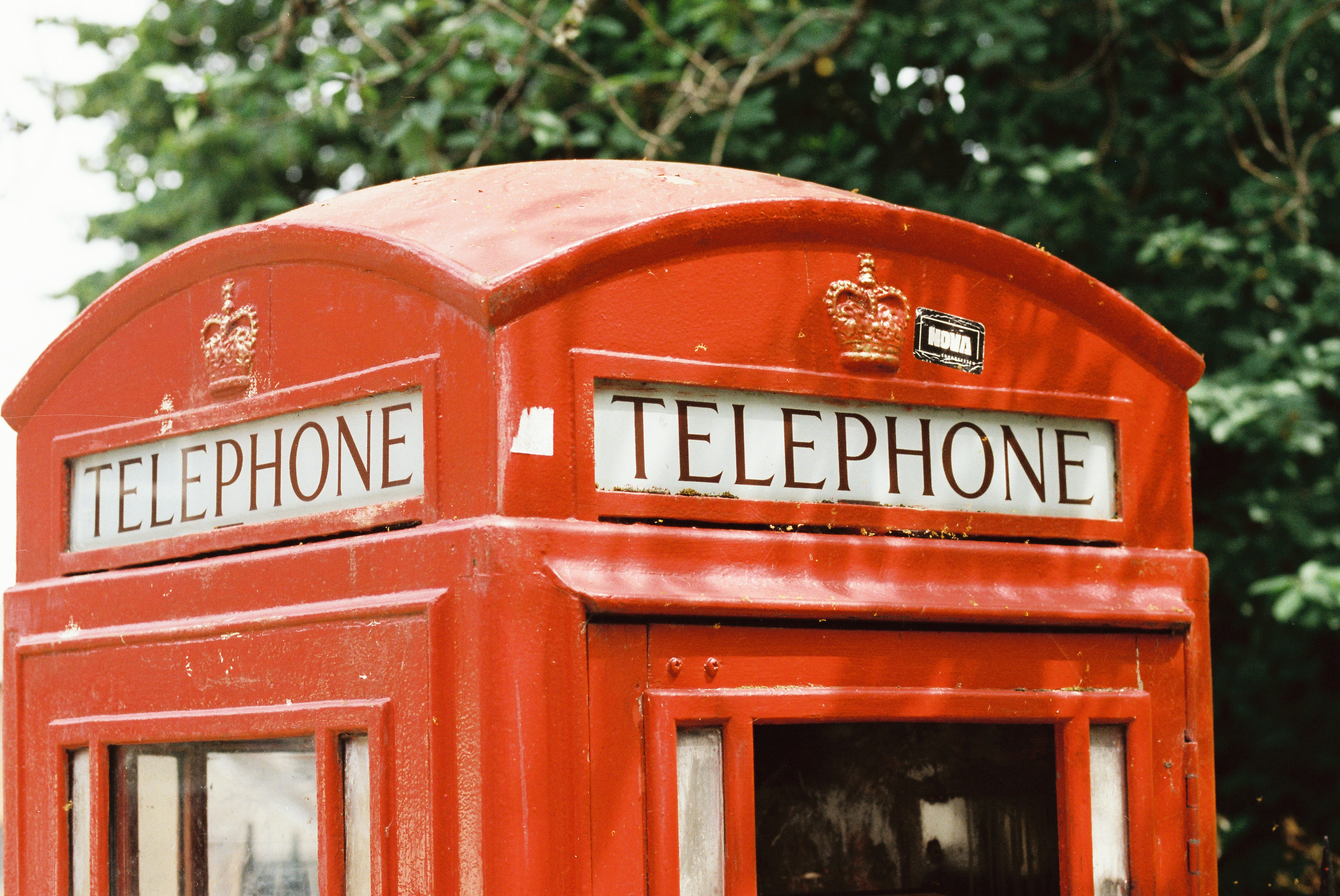 Crimson Landmark: A Classic Red UK Telephone Box Steeped in Greenery