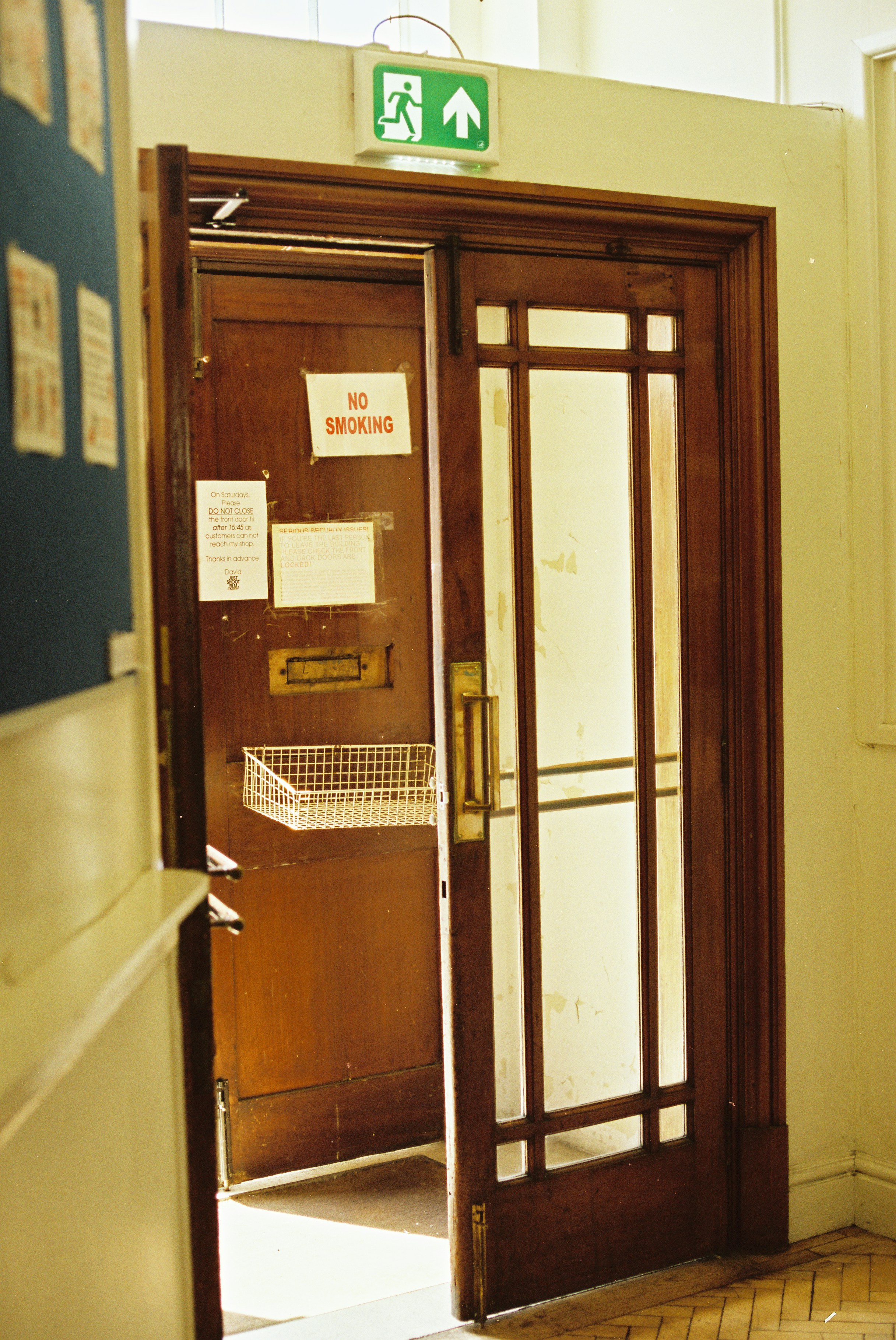 An open wooden door with a no smoking sign and green exit light frames a traditional interior threshold.