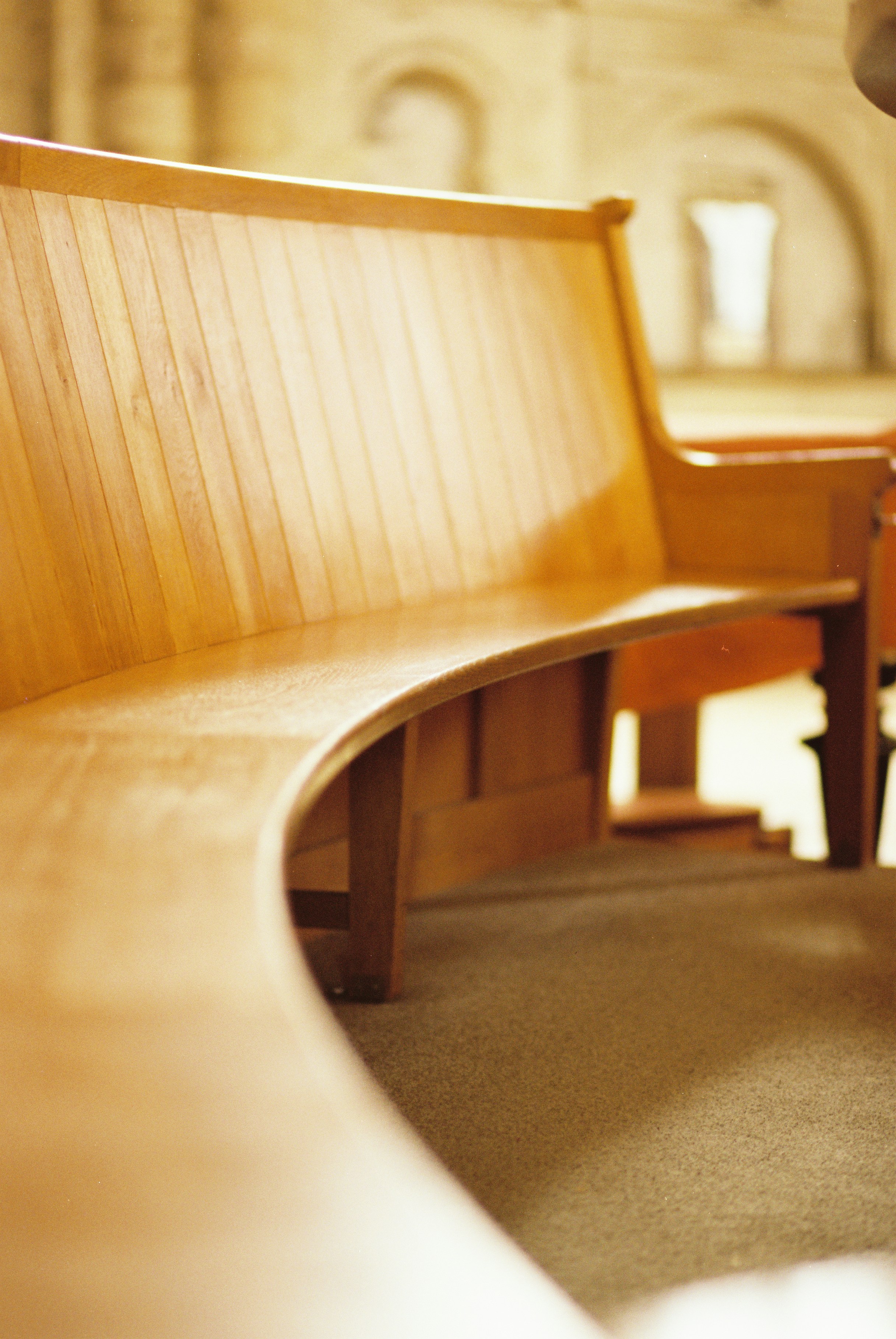 Curved Wooden Seating Leads the Eye Through Echoes of a Church Hall