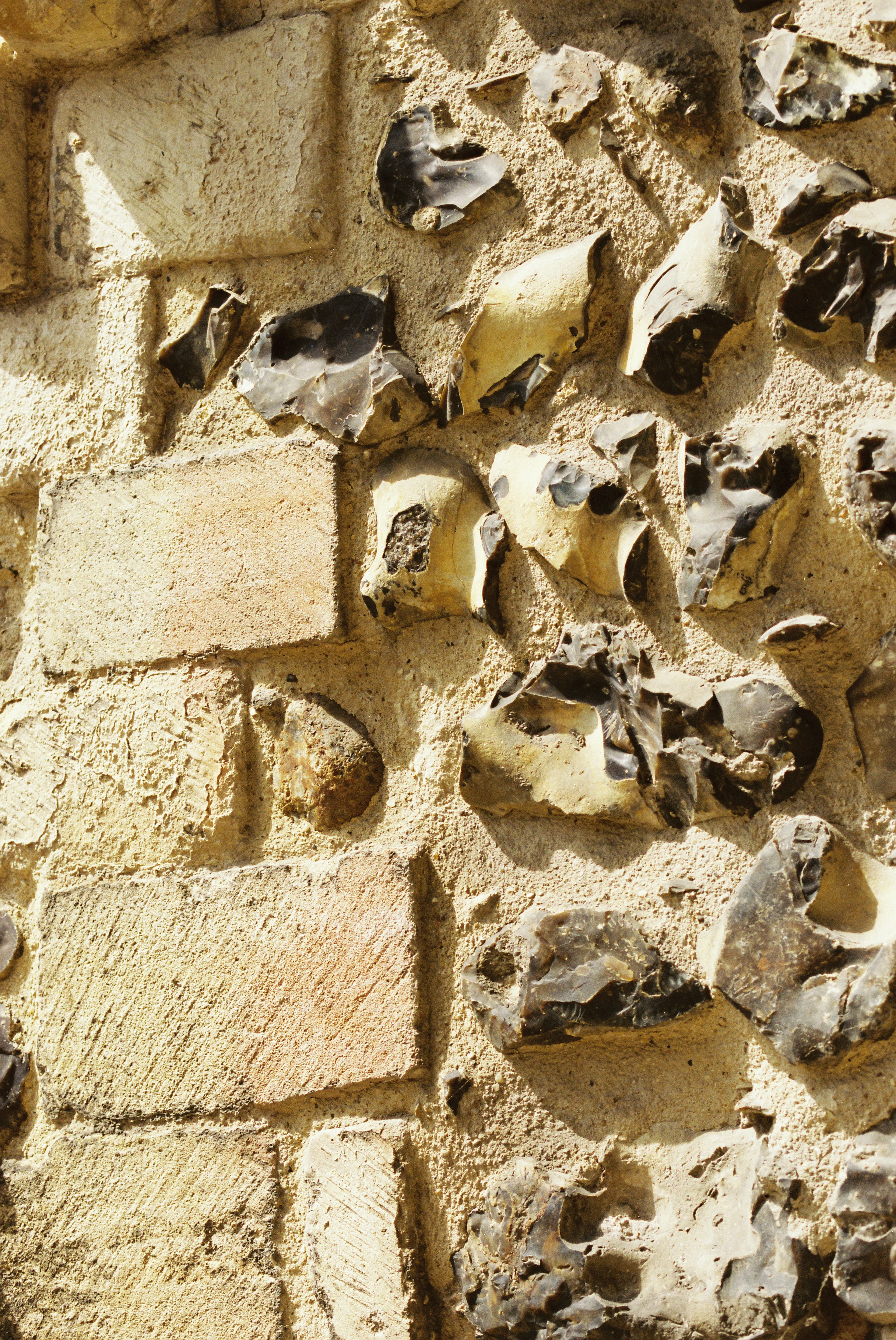 Stonework with scattered flint shards in warm sunlit mortar