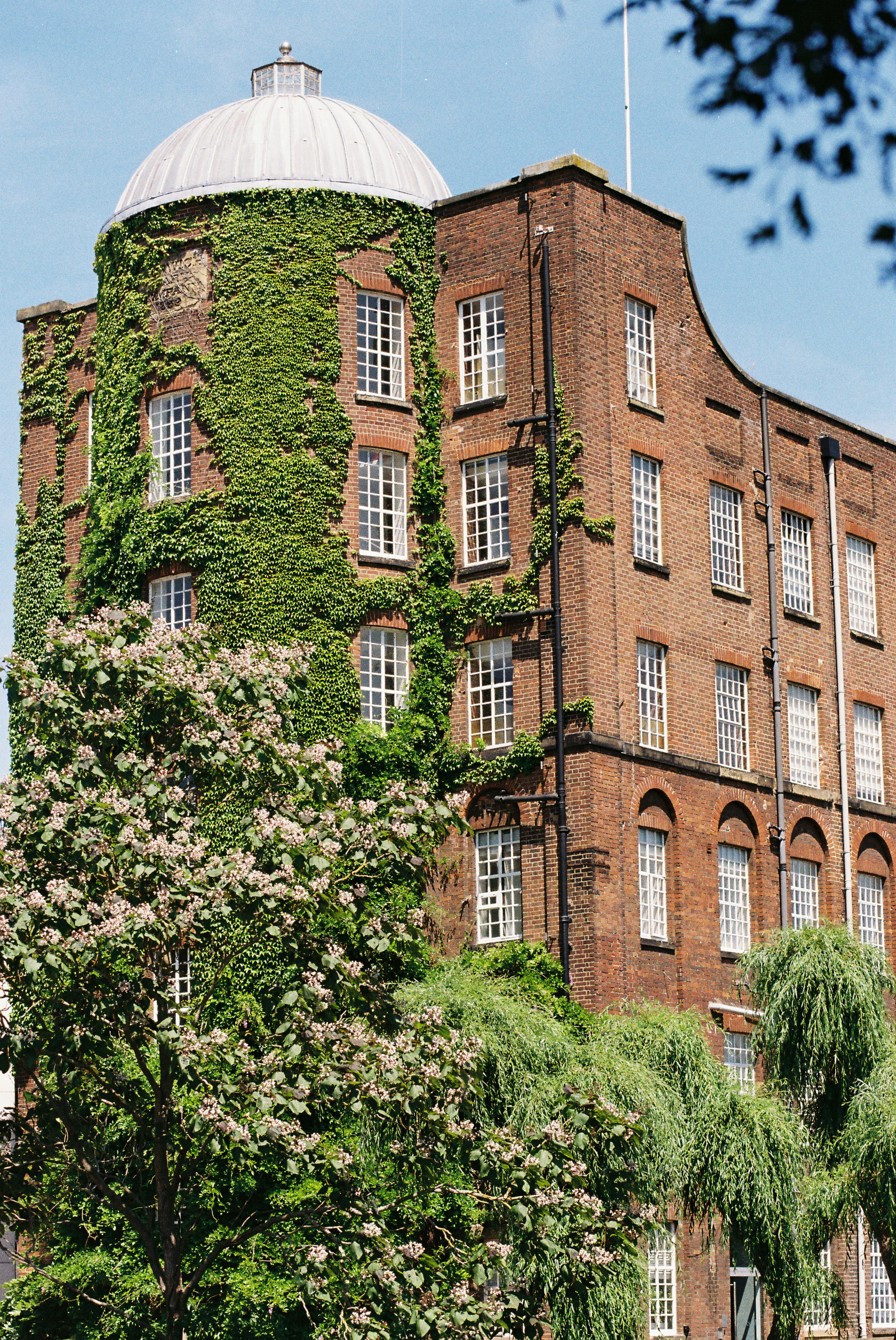Ivy-clad brick factory under a white domed turret