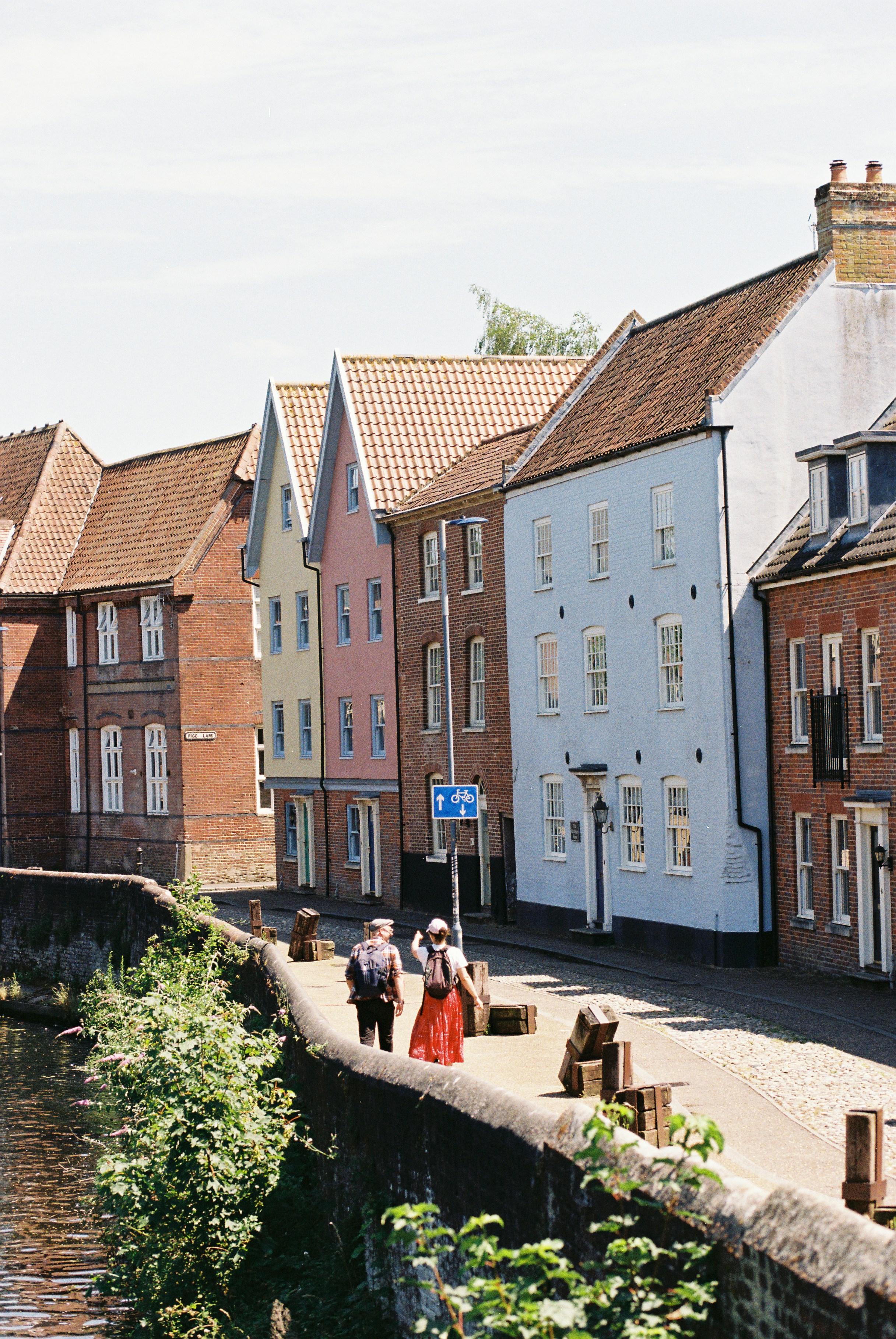 Pastel Row by the Canal: Walkway and Distant Pedestrians