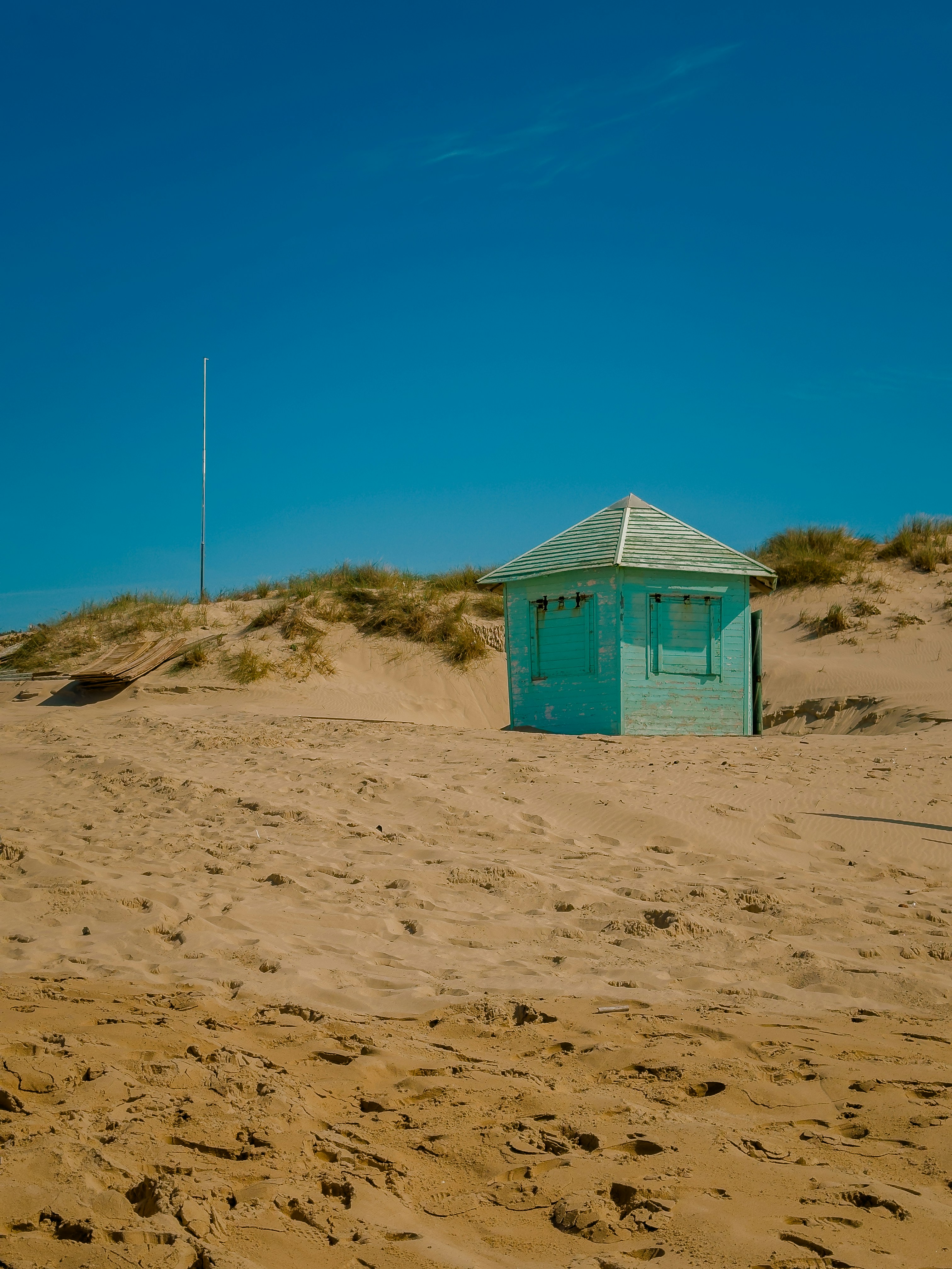 Coastal Watch: A Turquoise Lifeguard Cabin Beside Wind-Swept Dunes