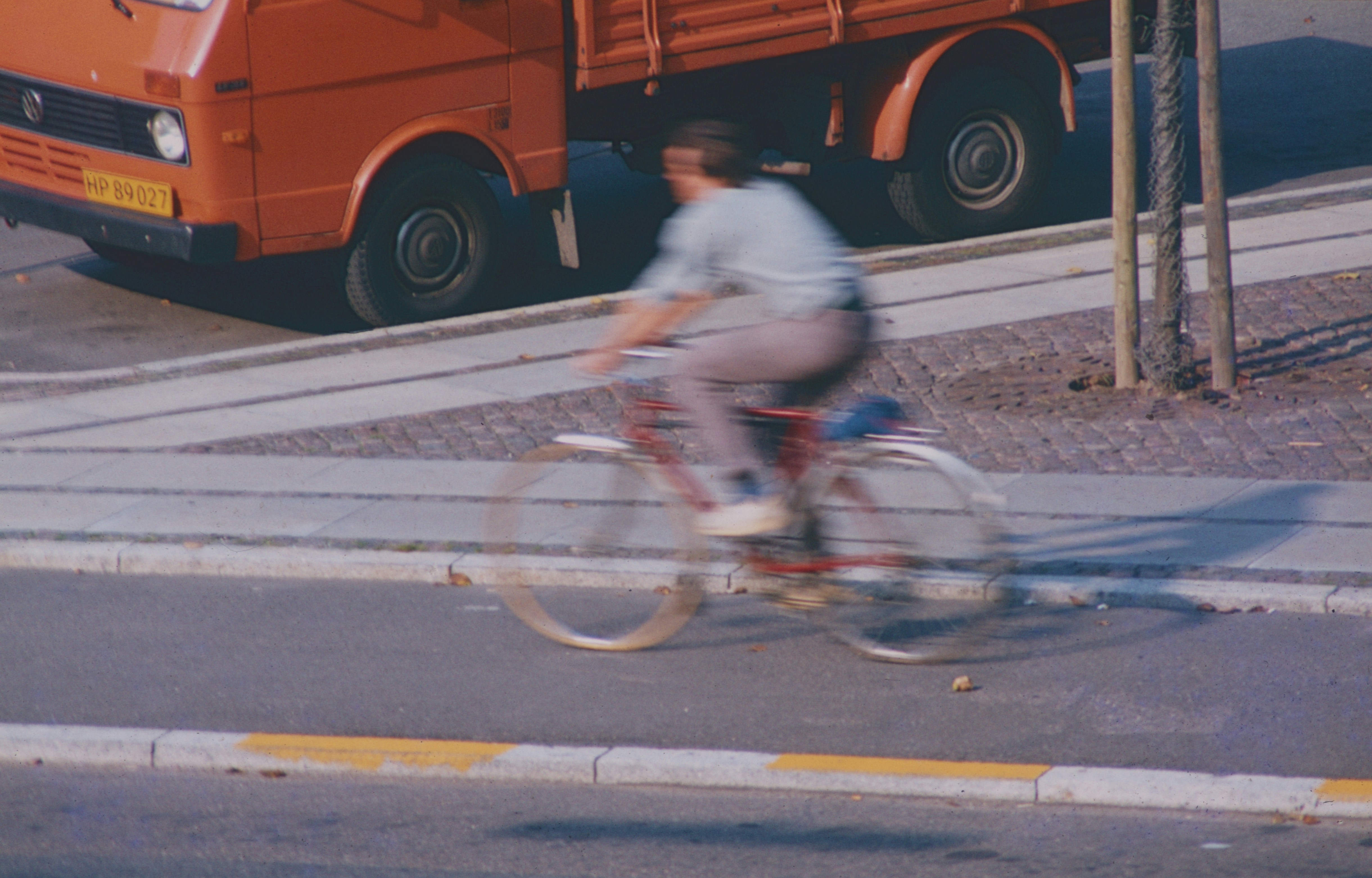 Blurry Cyclist in Motion by a Bright Orange Bus