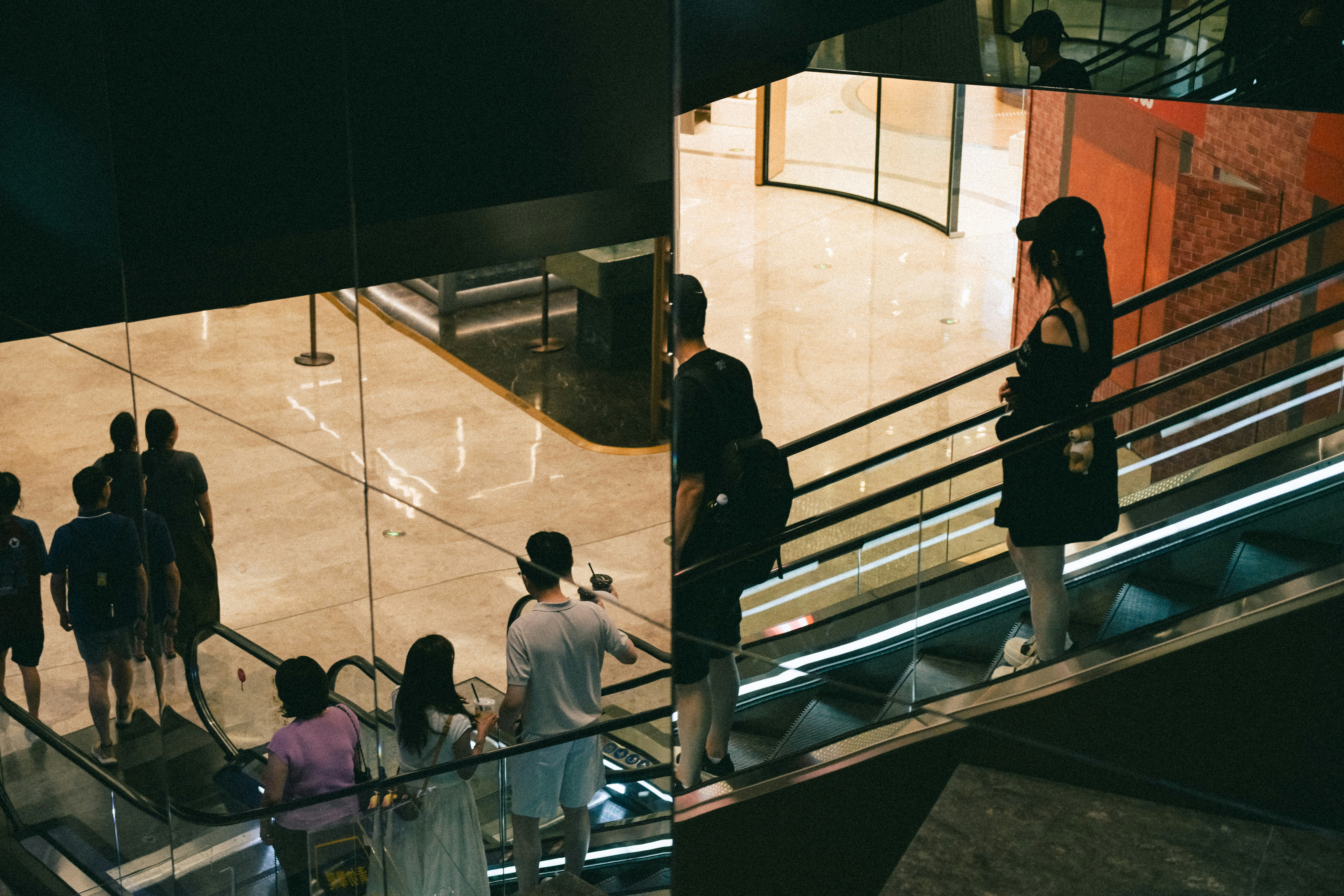 Escalator Choir: People Gathered on a Mall Escalator Plan Around a Modern Atrium