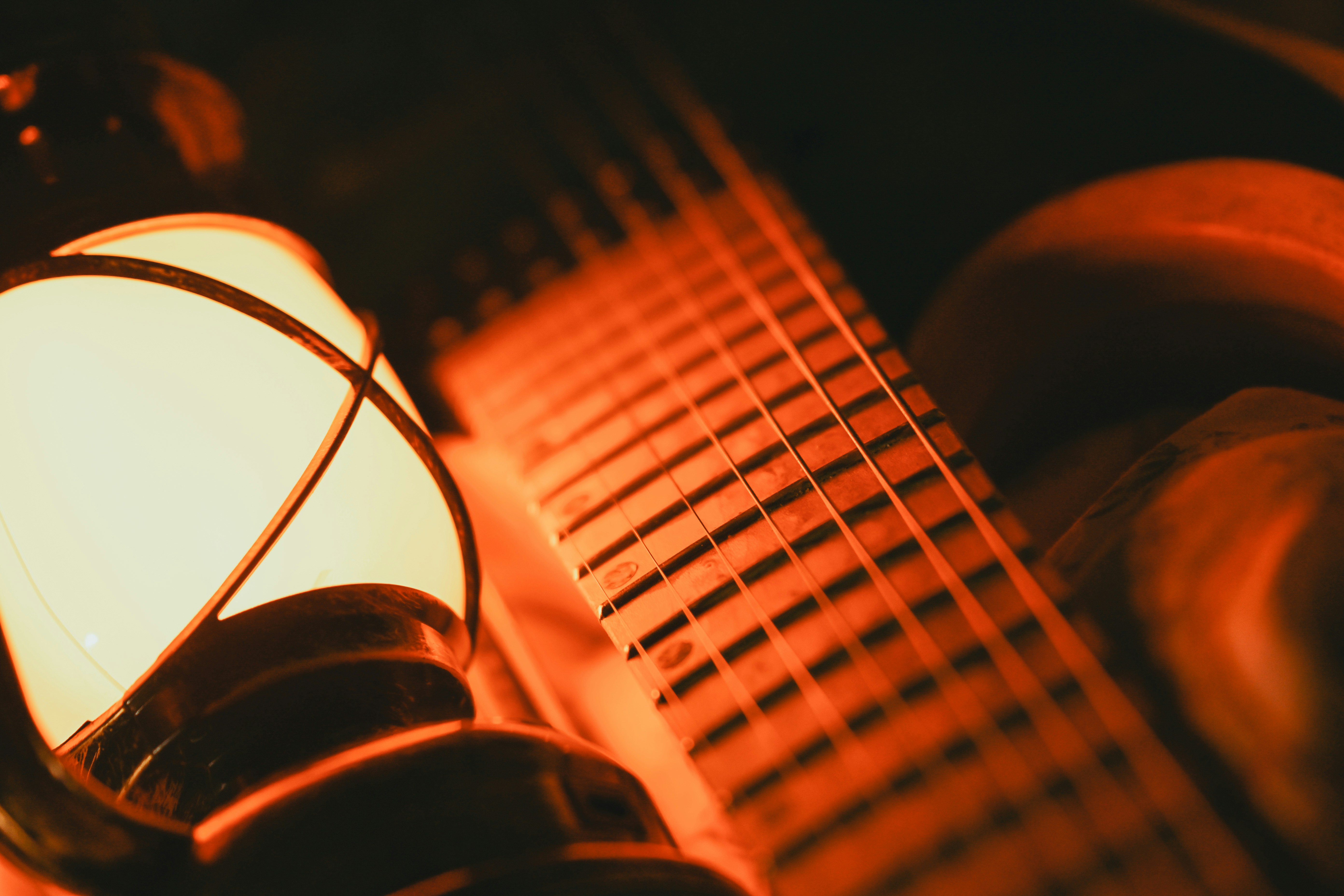 Warm Strings in a Sunset Lamp: A Close-Up of an Electric Guitar Neck in Ember Tones