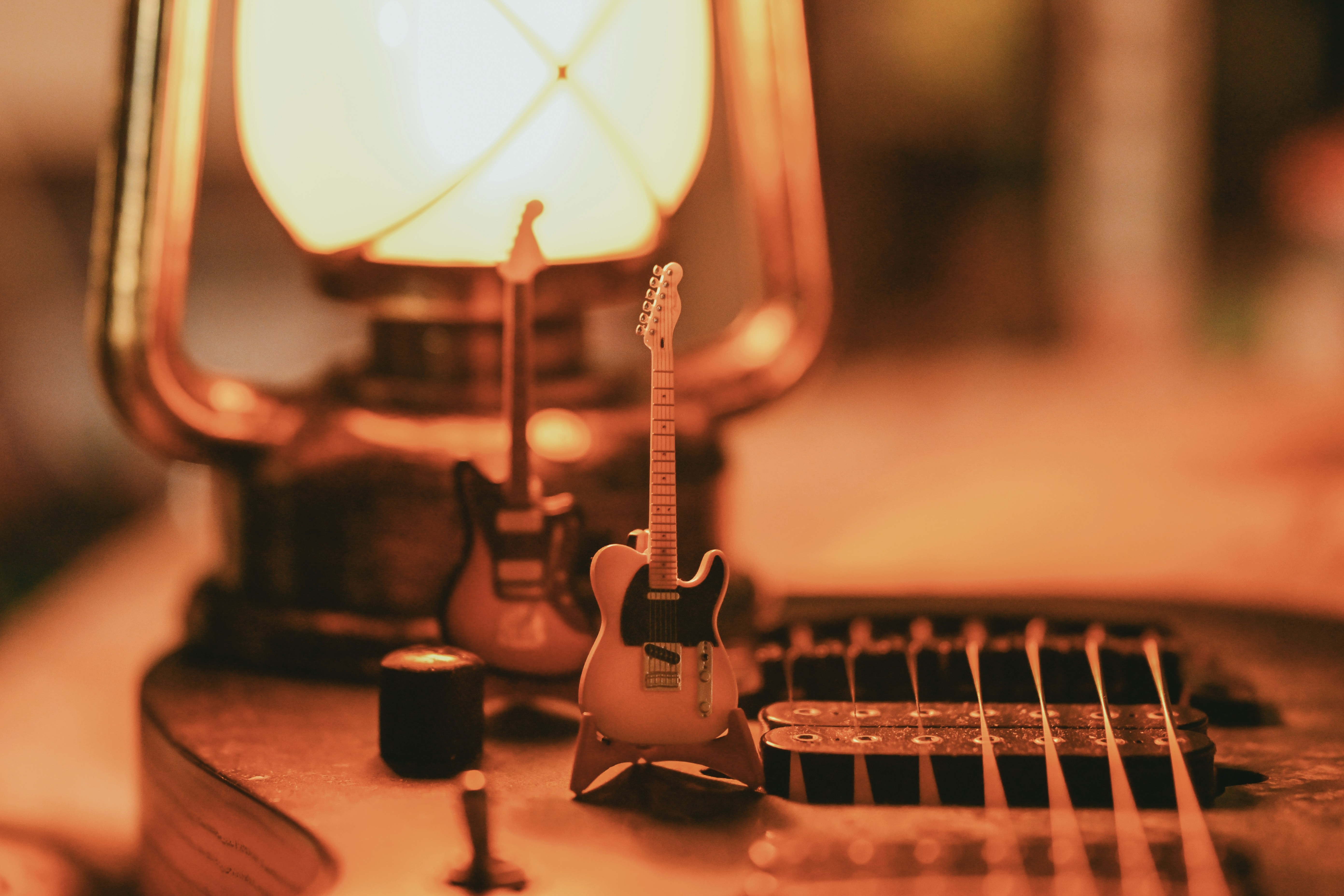 Miniature Telecaster on a Weathered Desk Under Warm Lamp Light