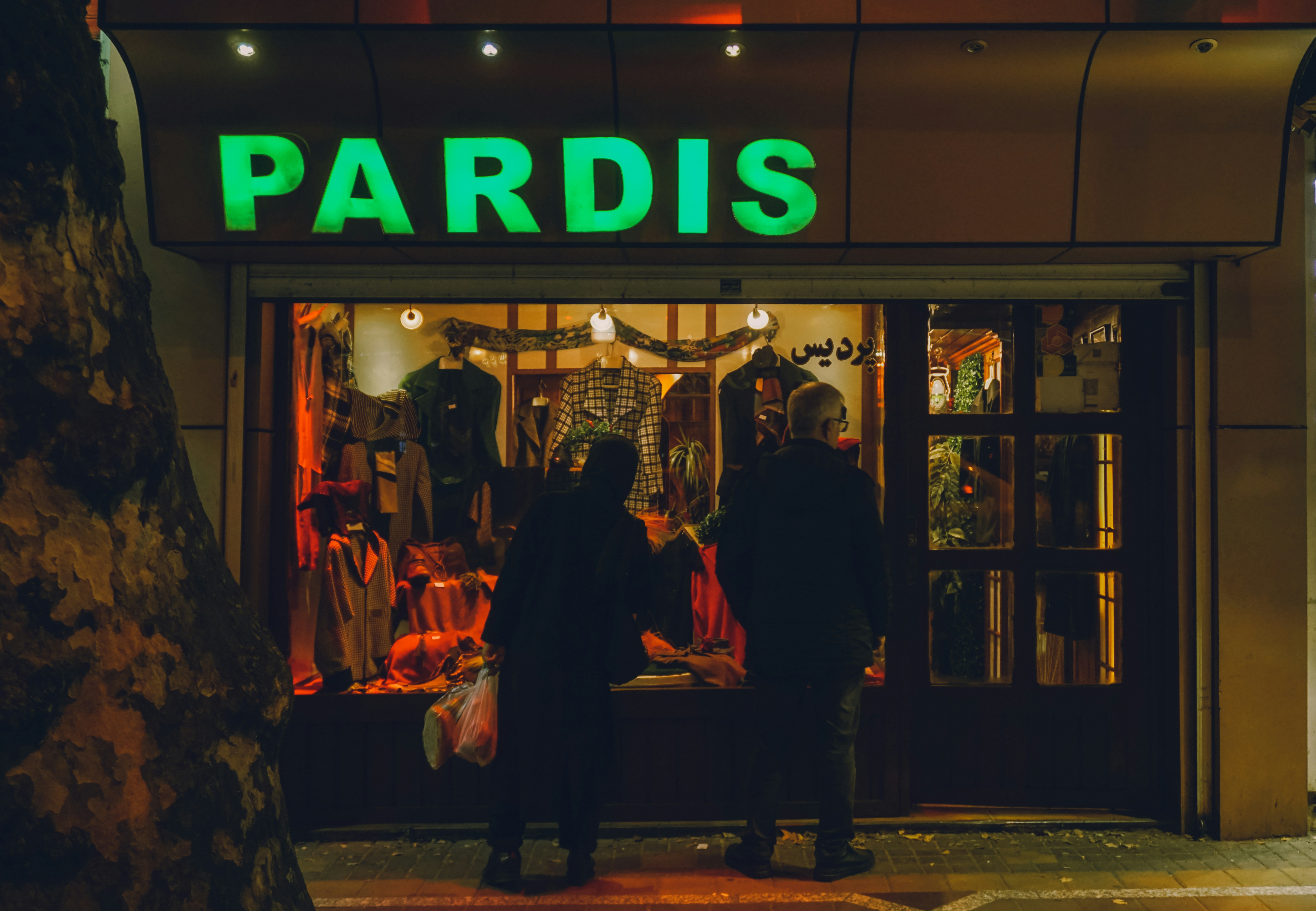 Green Sign, Quiet Crowd: Night Life at a Storefront Window