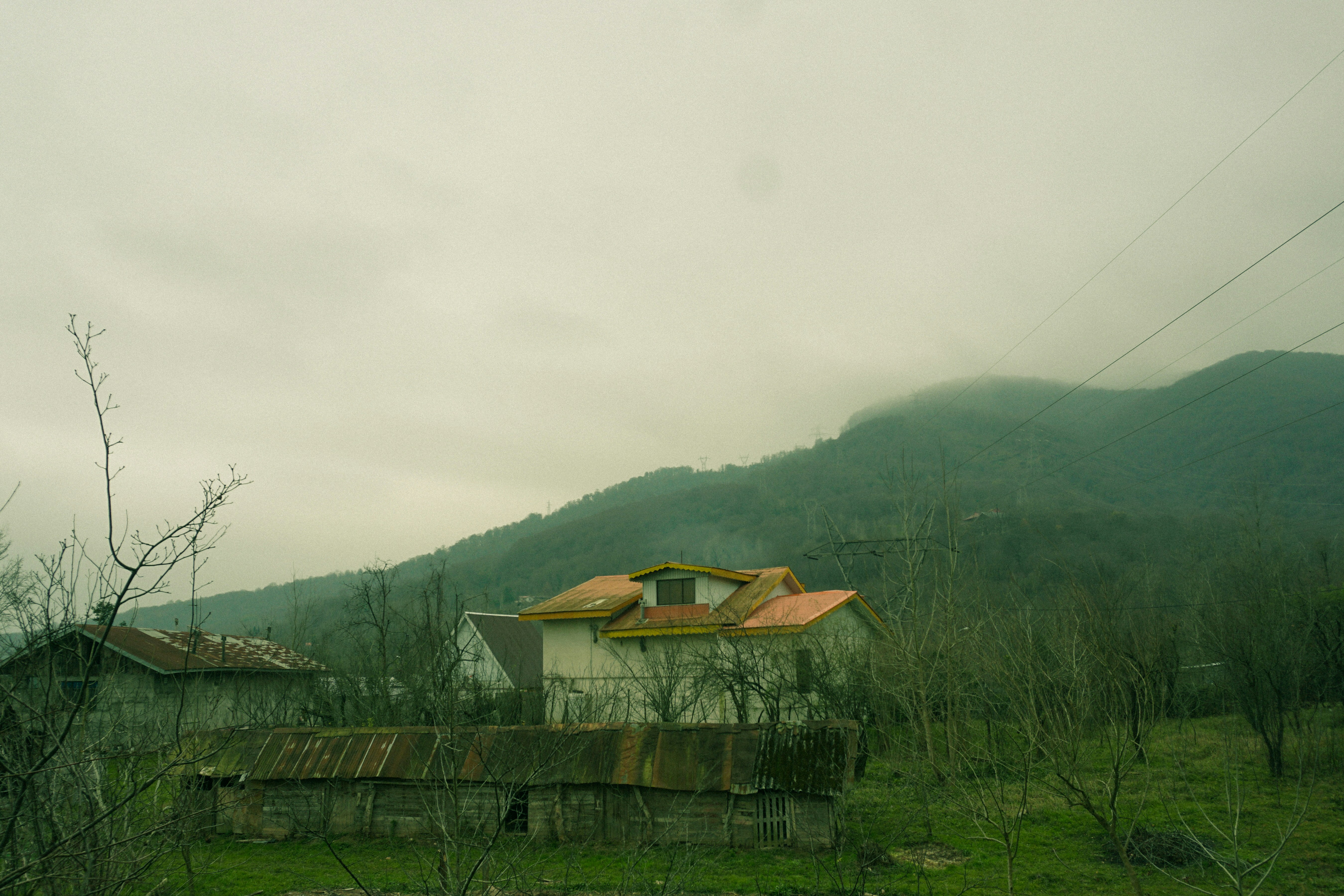 Rural house beneath misty hills in early spring